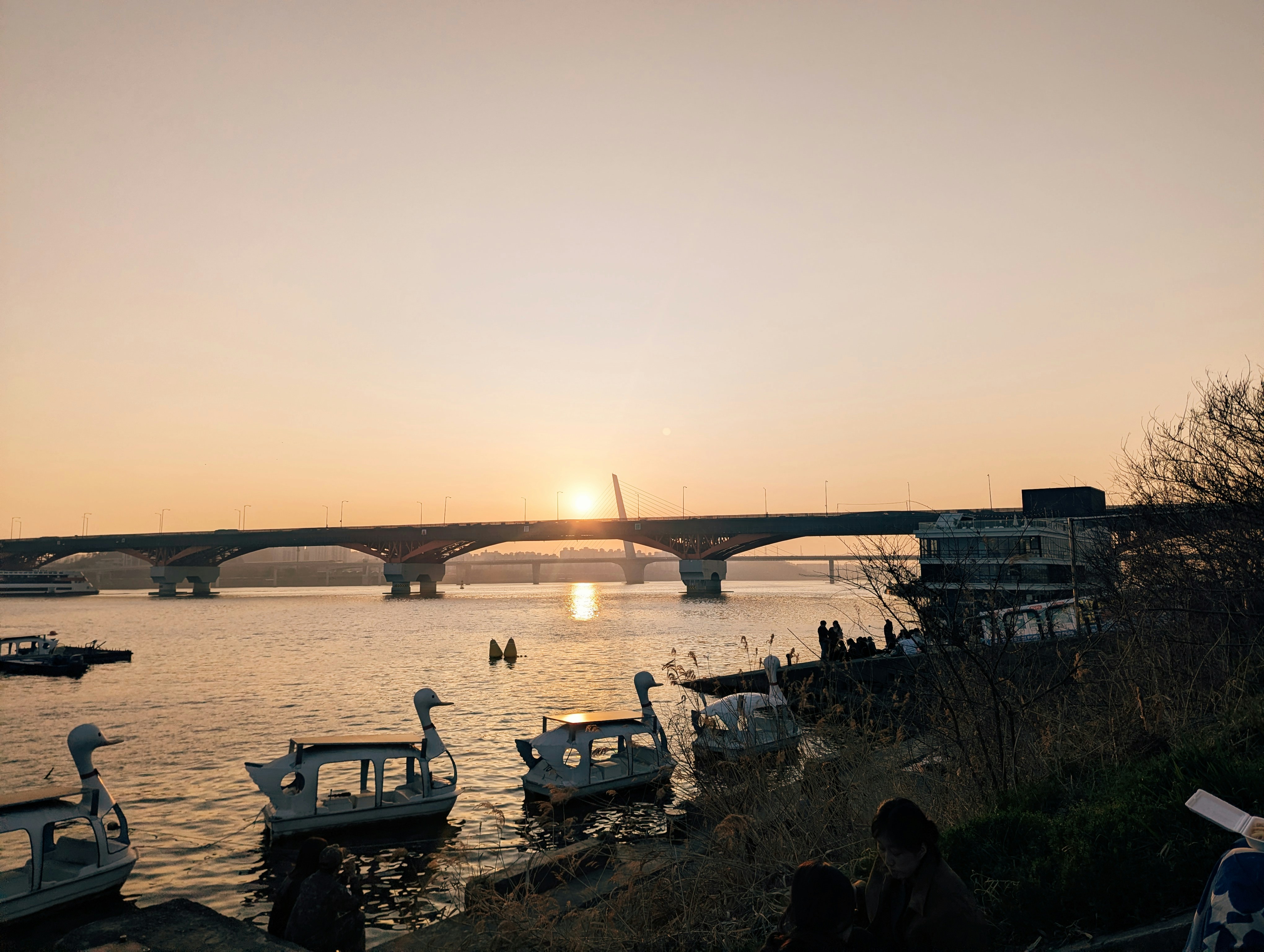Sunset Over the River: Pedal Boats and a Silent Bridge
