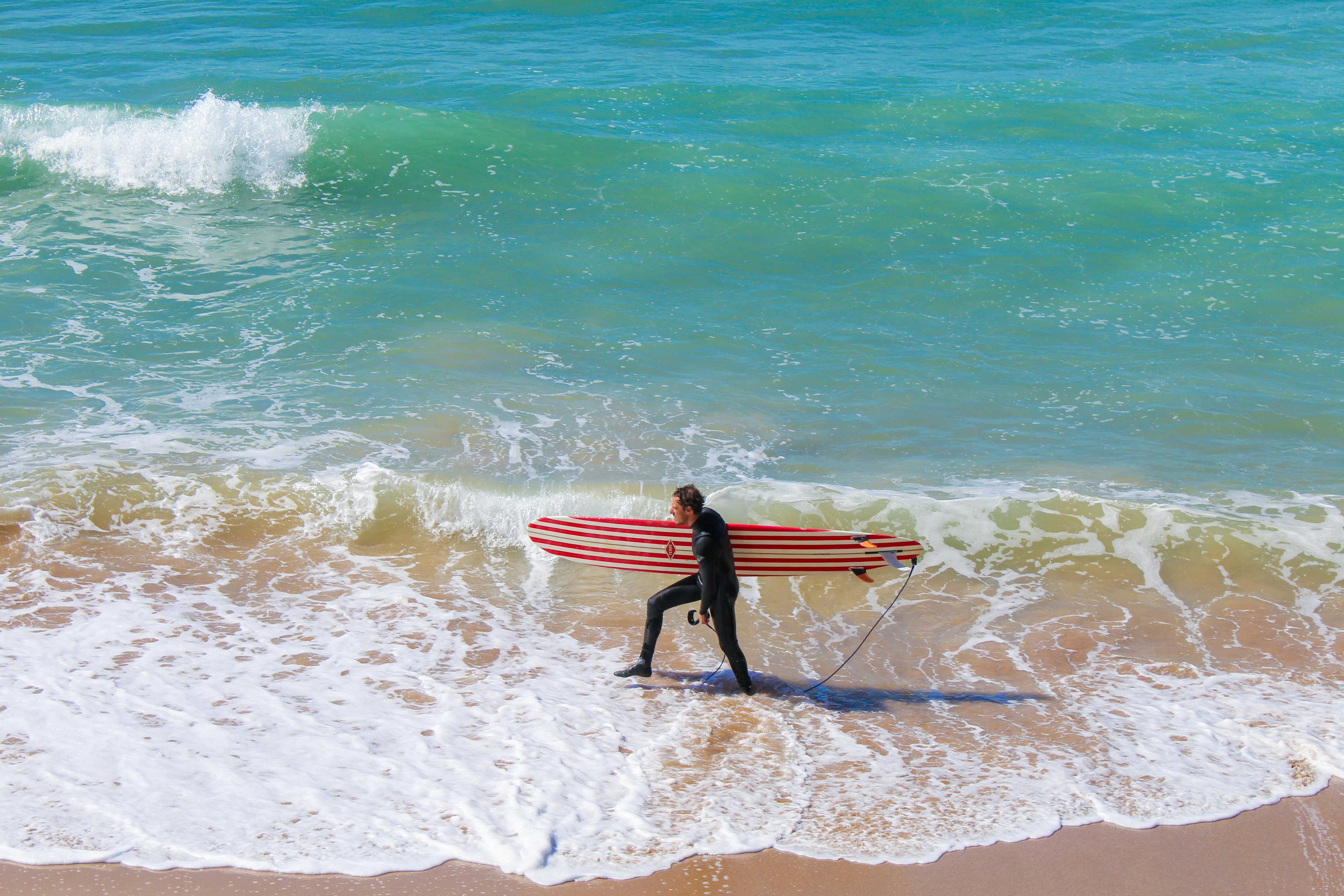 Surfer with the Red-Wanded Surfboard Crossing Cresting Tides