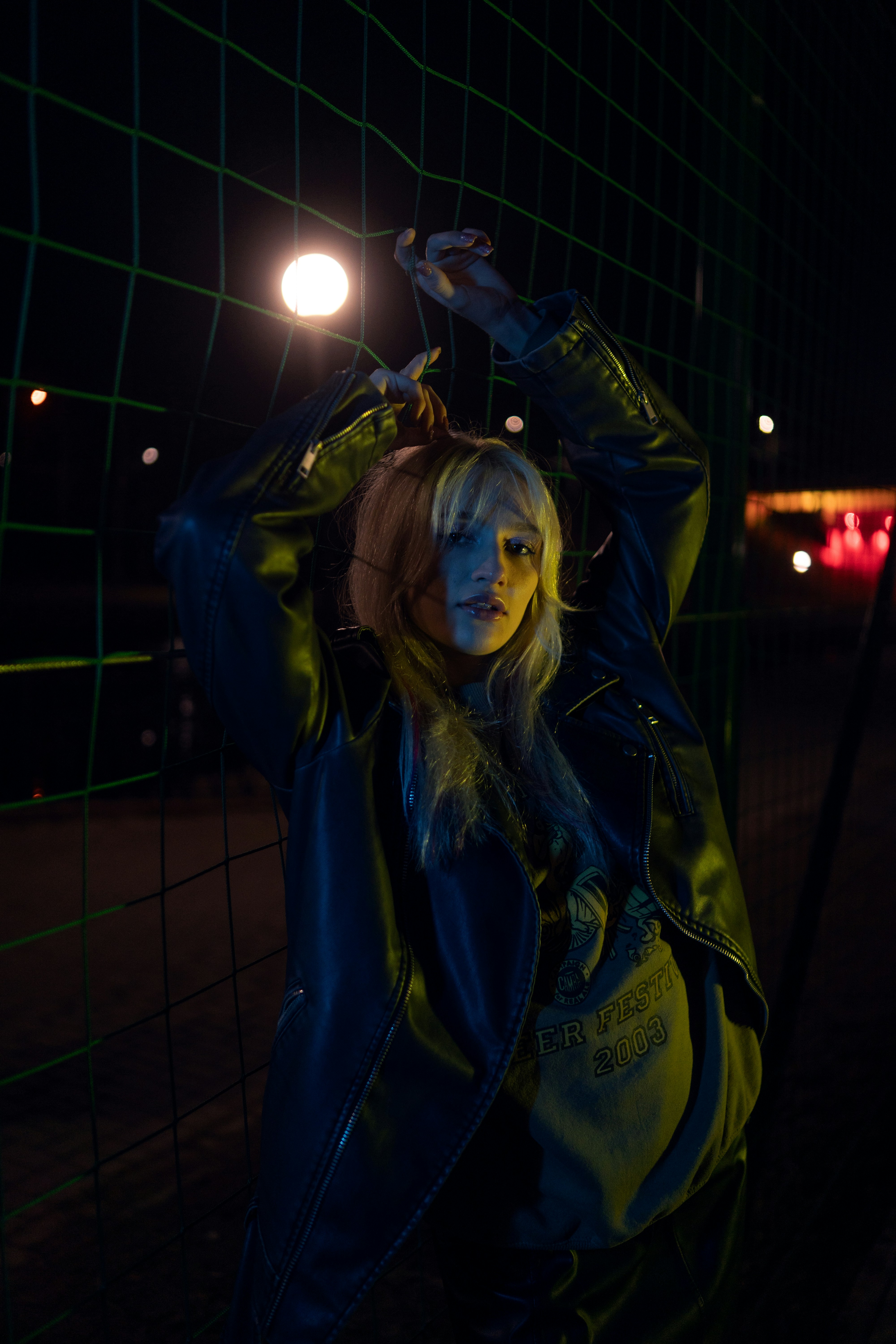Neon-lit Night: A Youthful Gaze Through a Green Fence