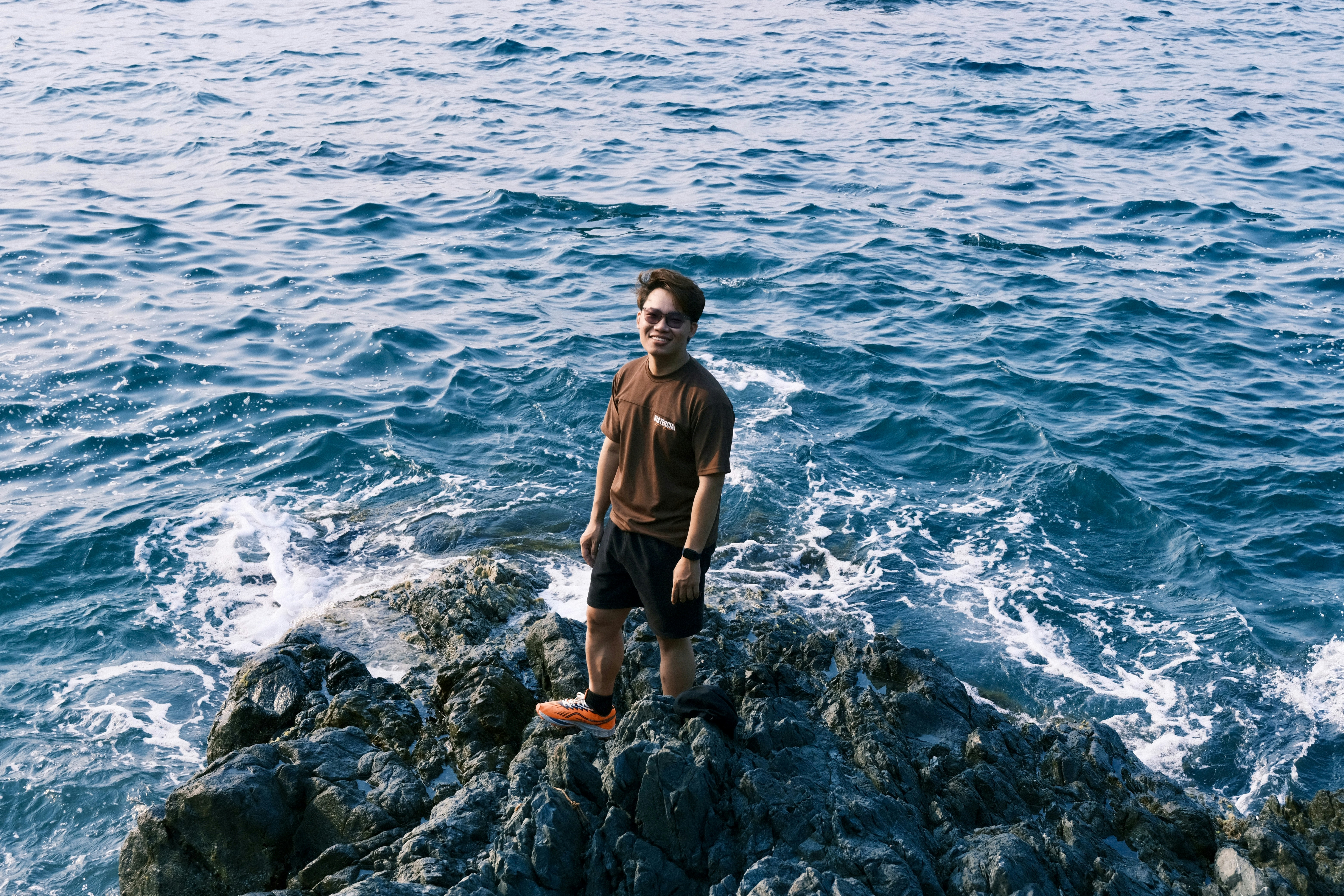 Rugged Prominence: Man Stands Afloat on Coastal Rocks