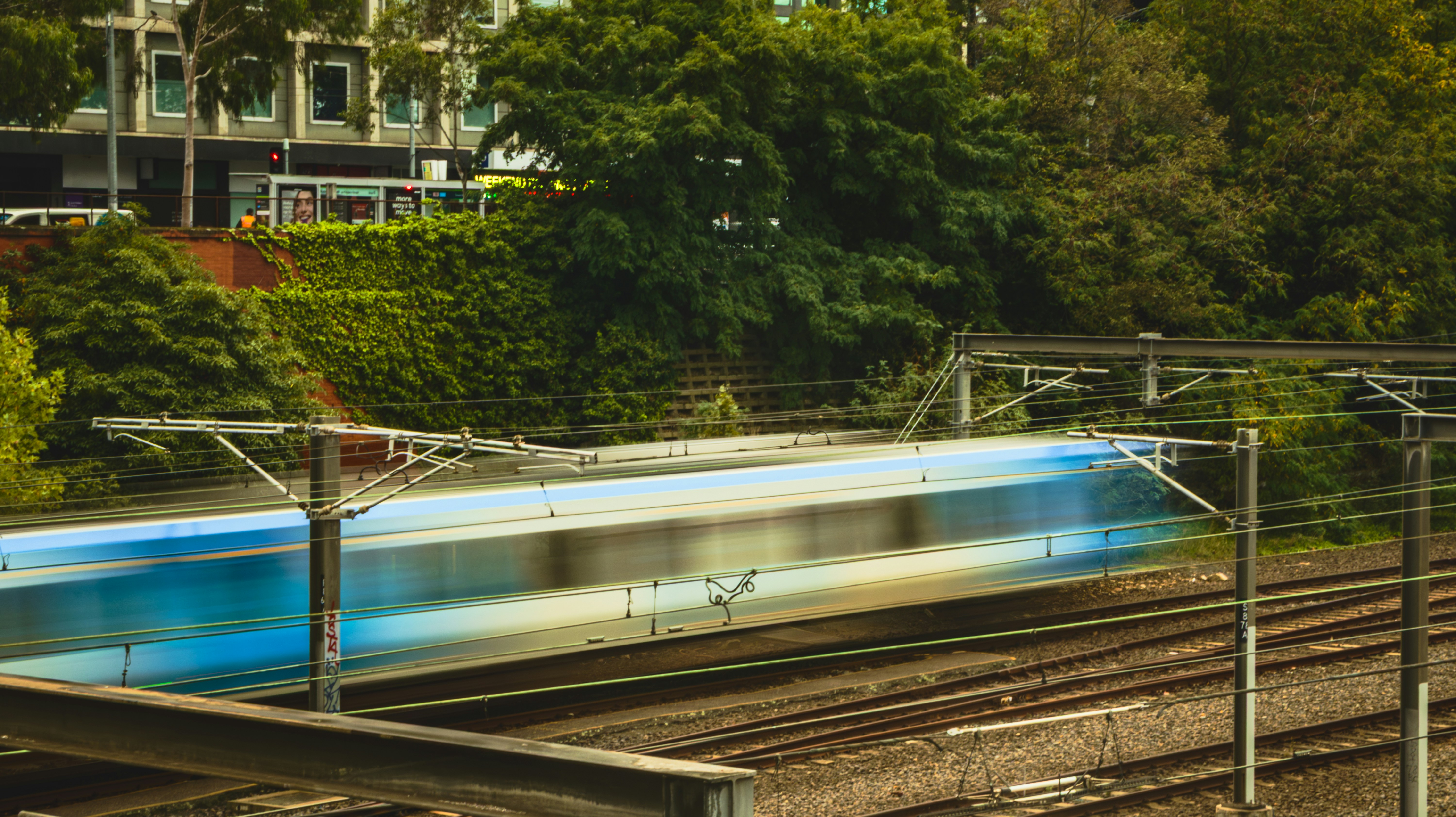 Blurred Train Passage Over Tracks Through Urban Greenery