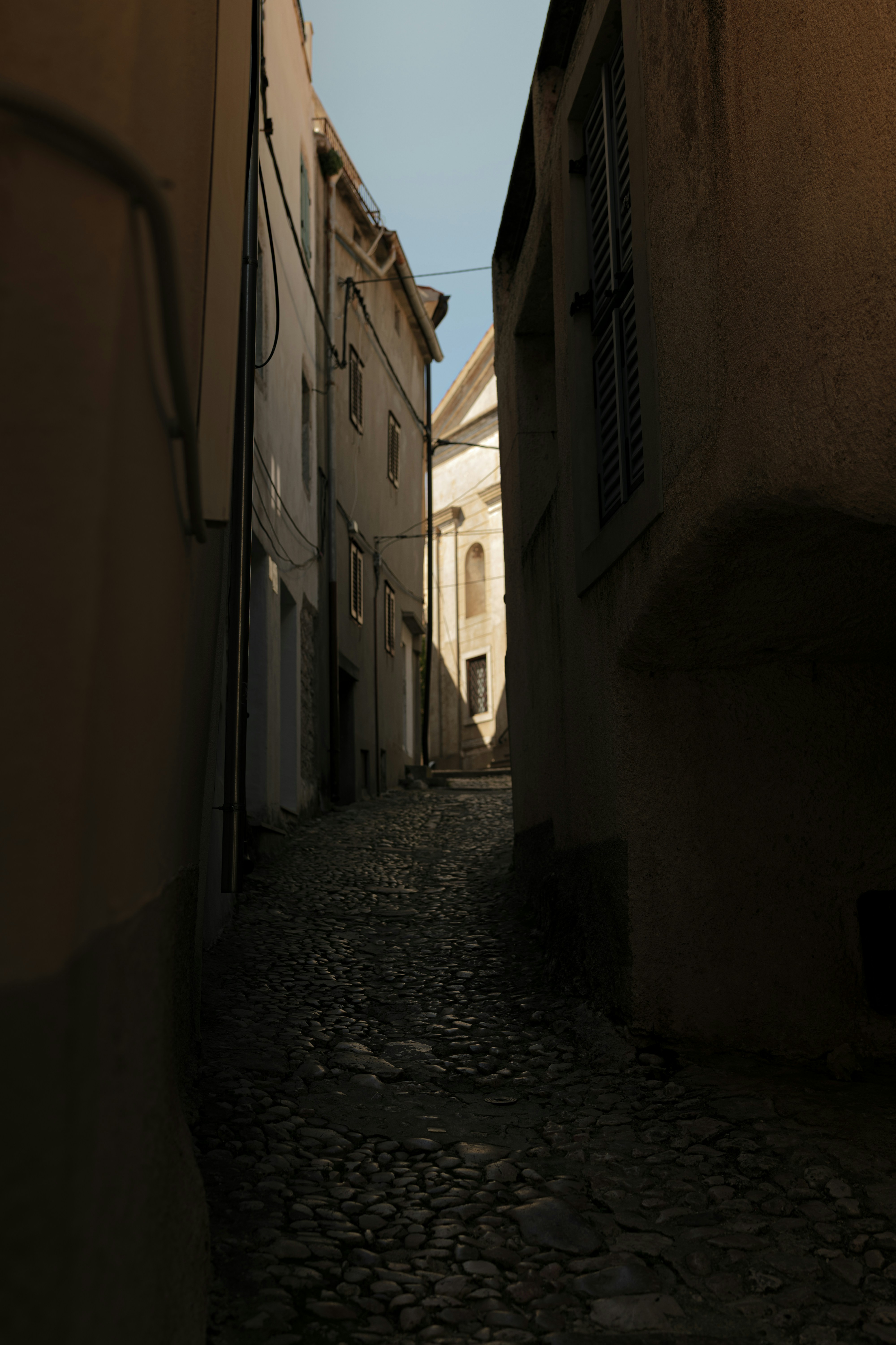 Narrow Passage to Light: A Cobblestone Street Reaching for the Sun