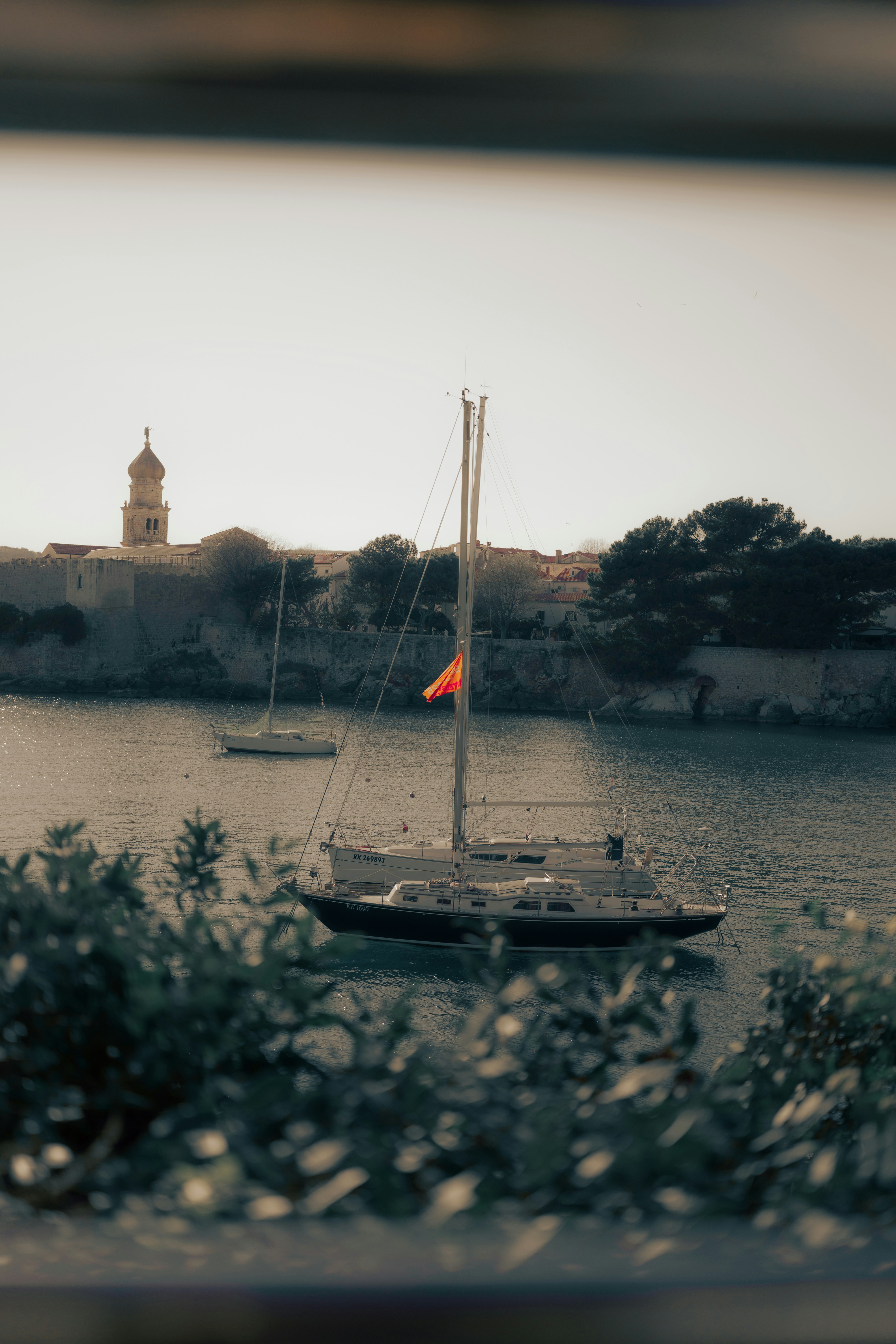 Sailing Quiet: A Sailboat Anchored by a Coastal Town