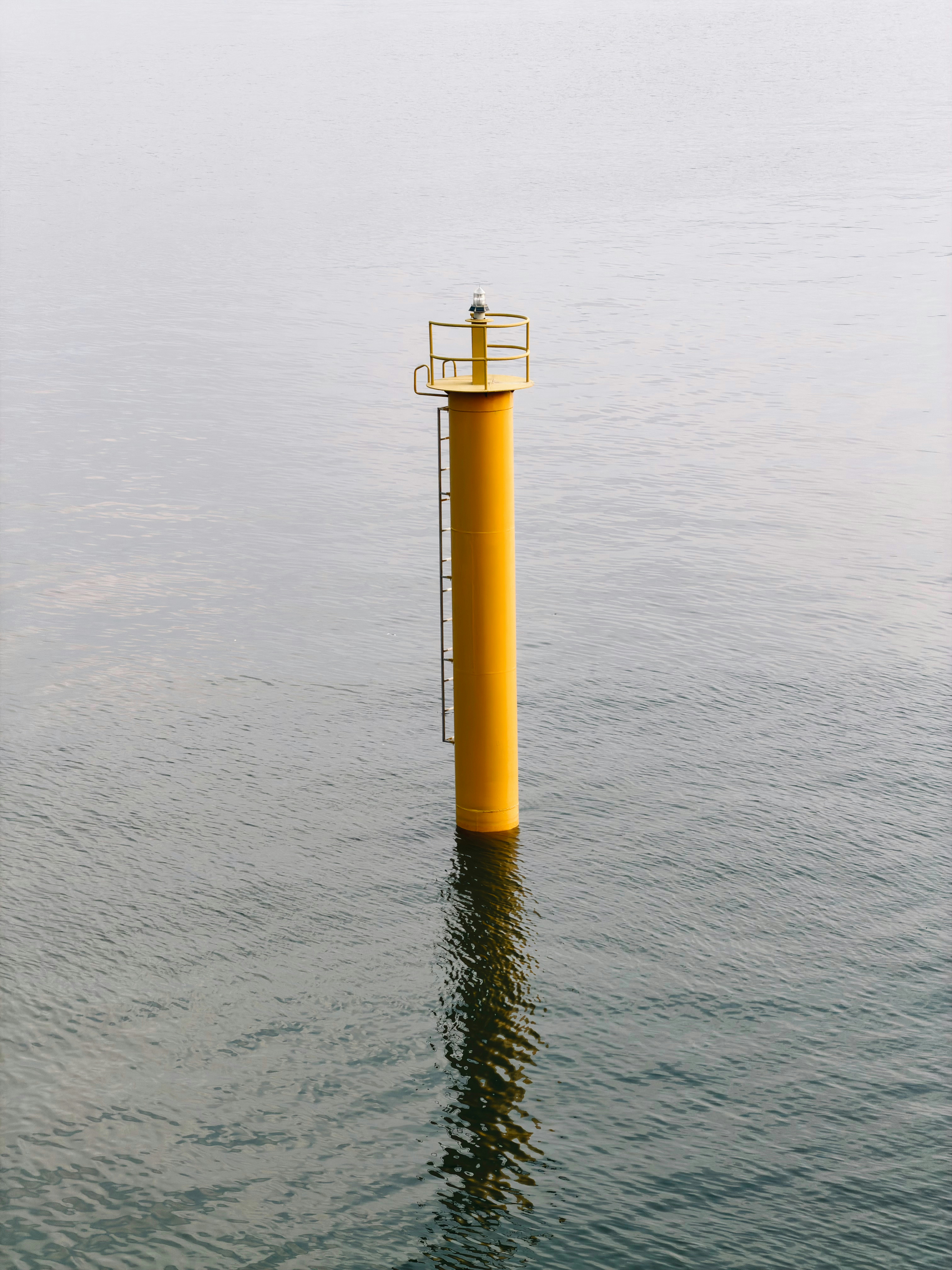 A solitary yellow beacon rising from glassy water