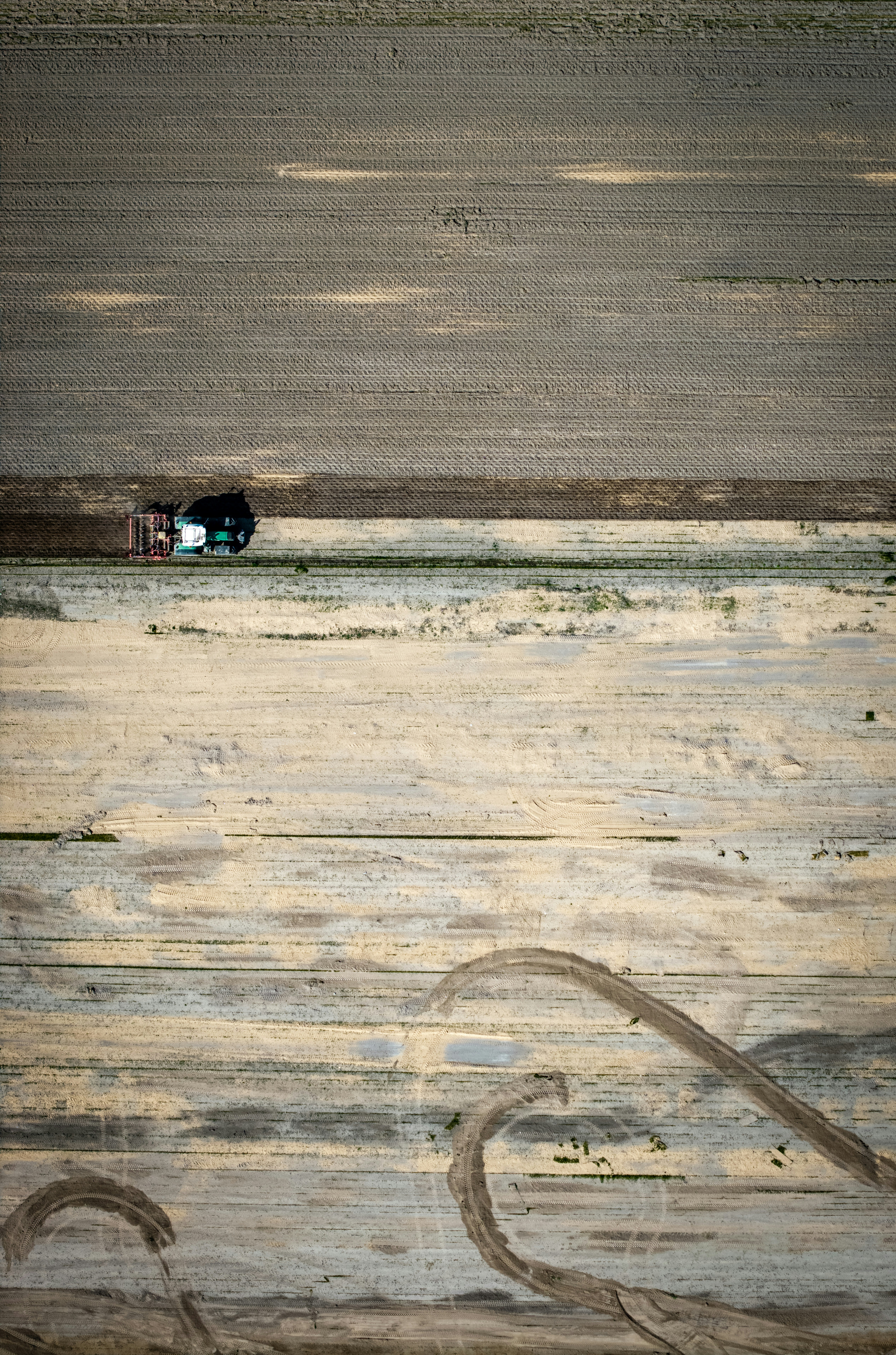 Tractor along a weathered coastline: an aerial tilt over a rugged field