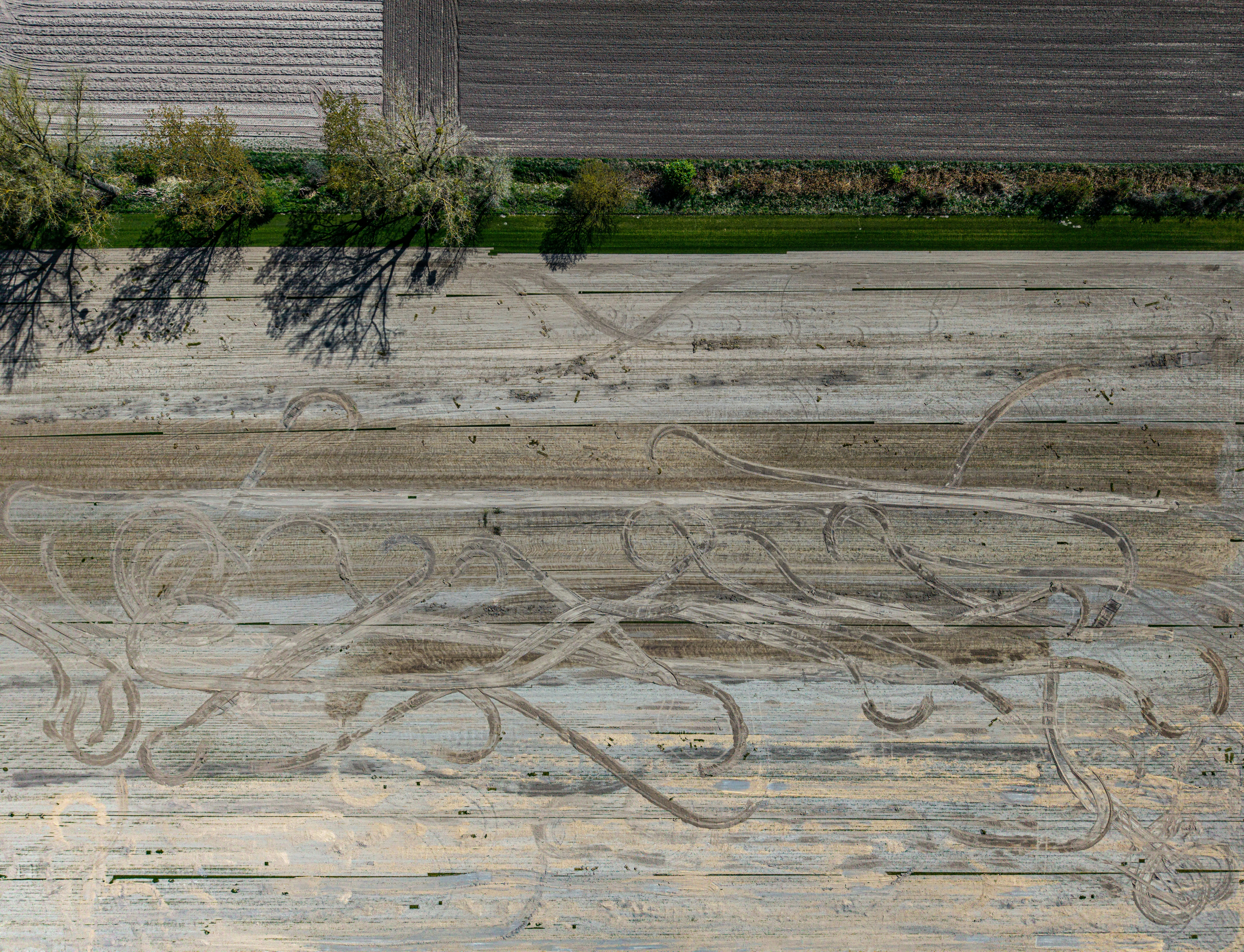 Aerial view of a plowed agricultural field with tire tracks.