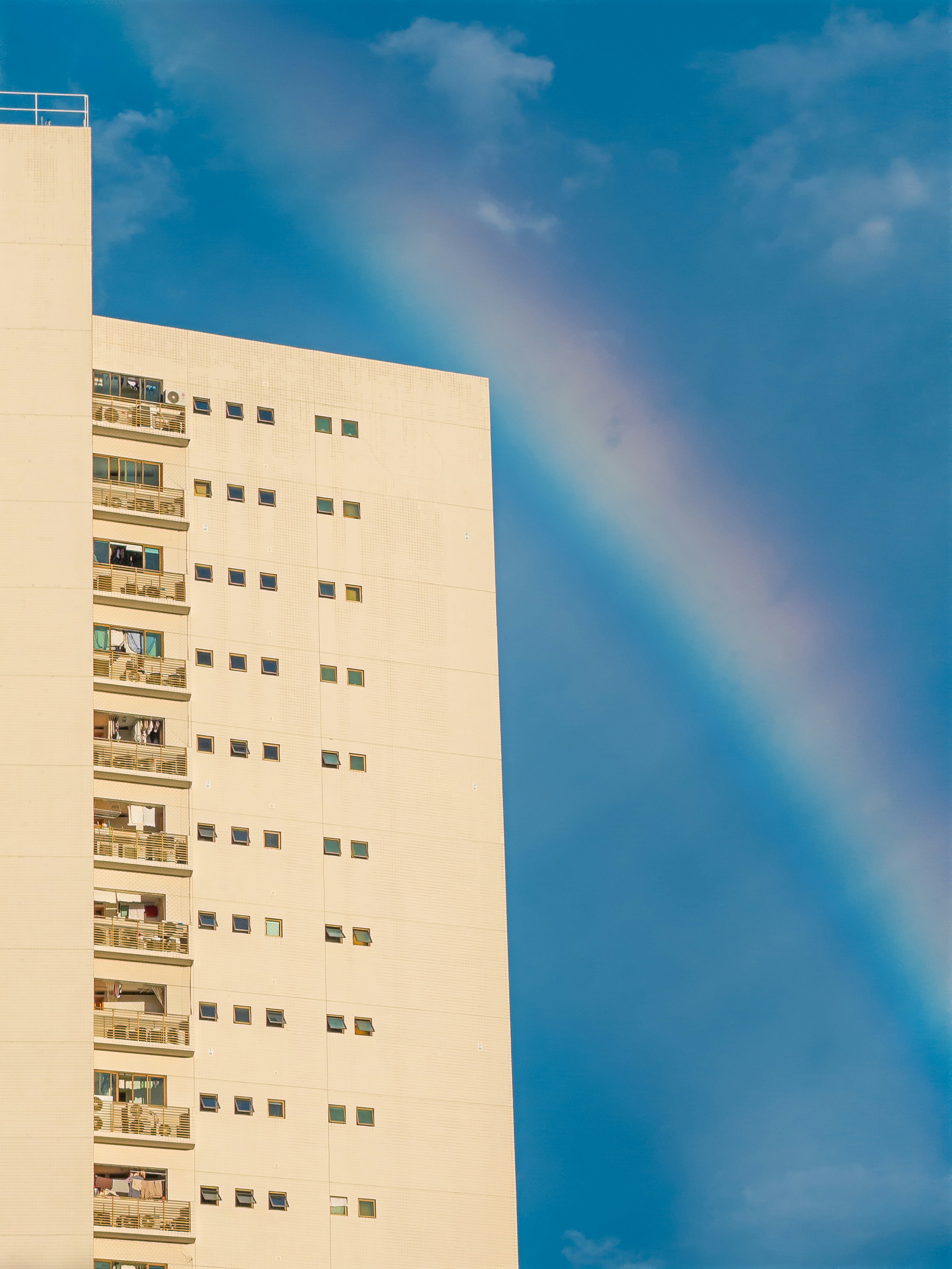 Rainbow Archover: A Sunlit Apartment Tower Against a Sky