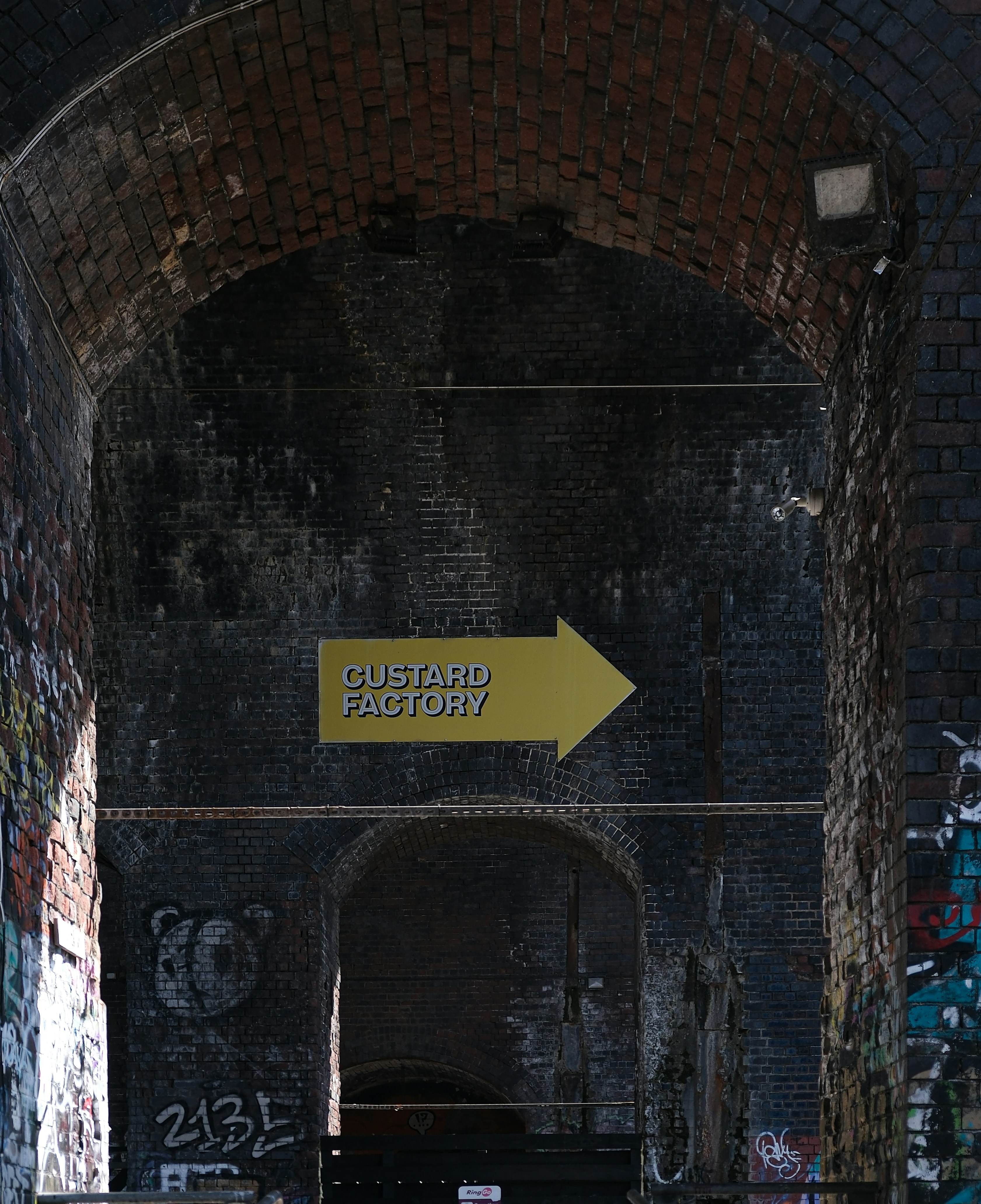 Yellow Arrow Over Dark Archway: Guiding Light in a Graffiti-Scarred Passage