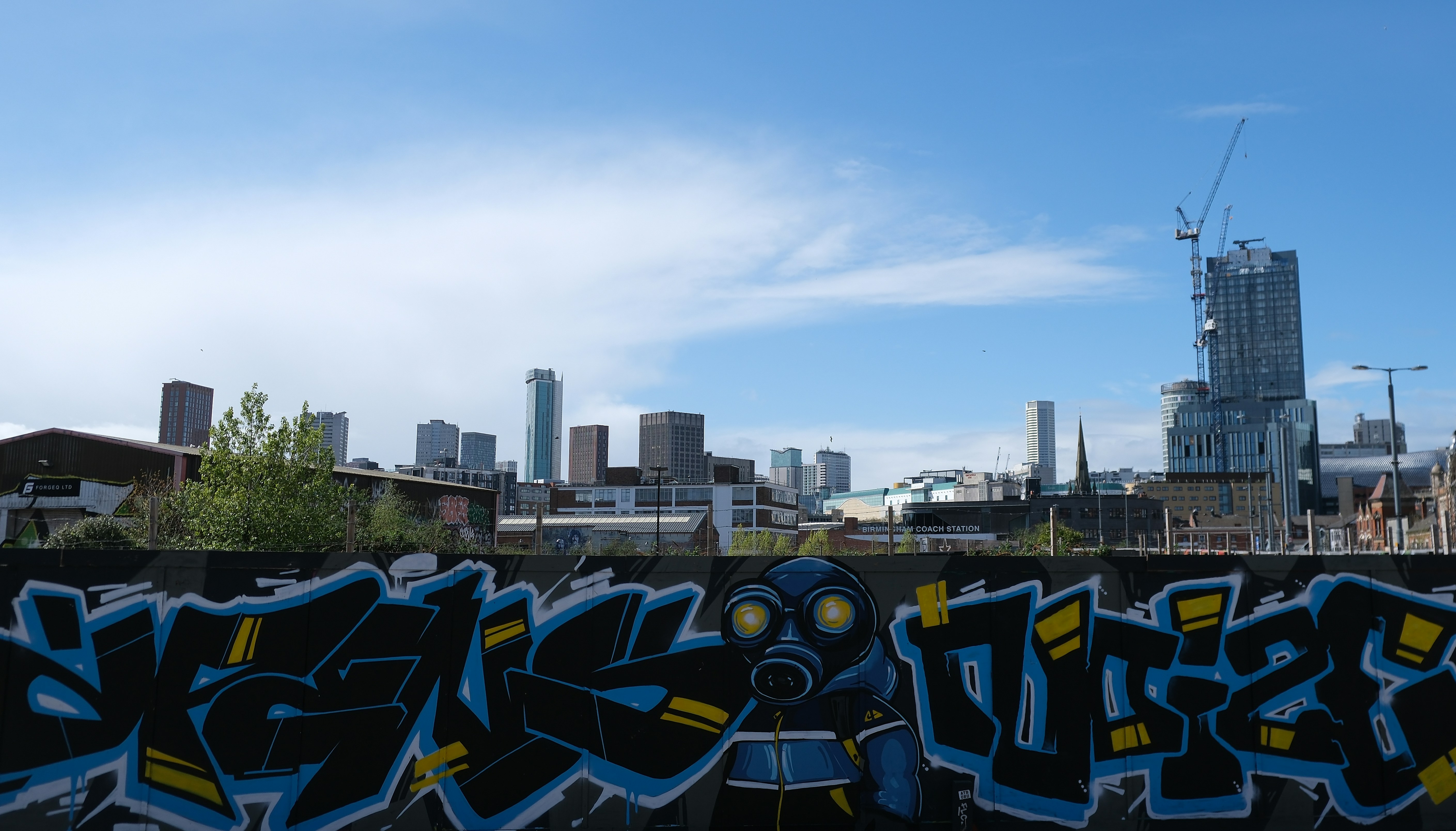 City skyline behind a bold graffiti mural under a bright sky