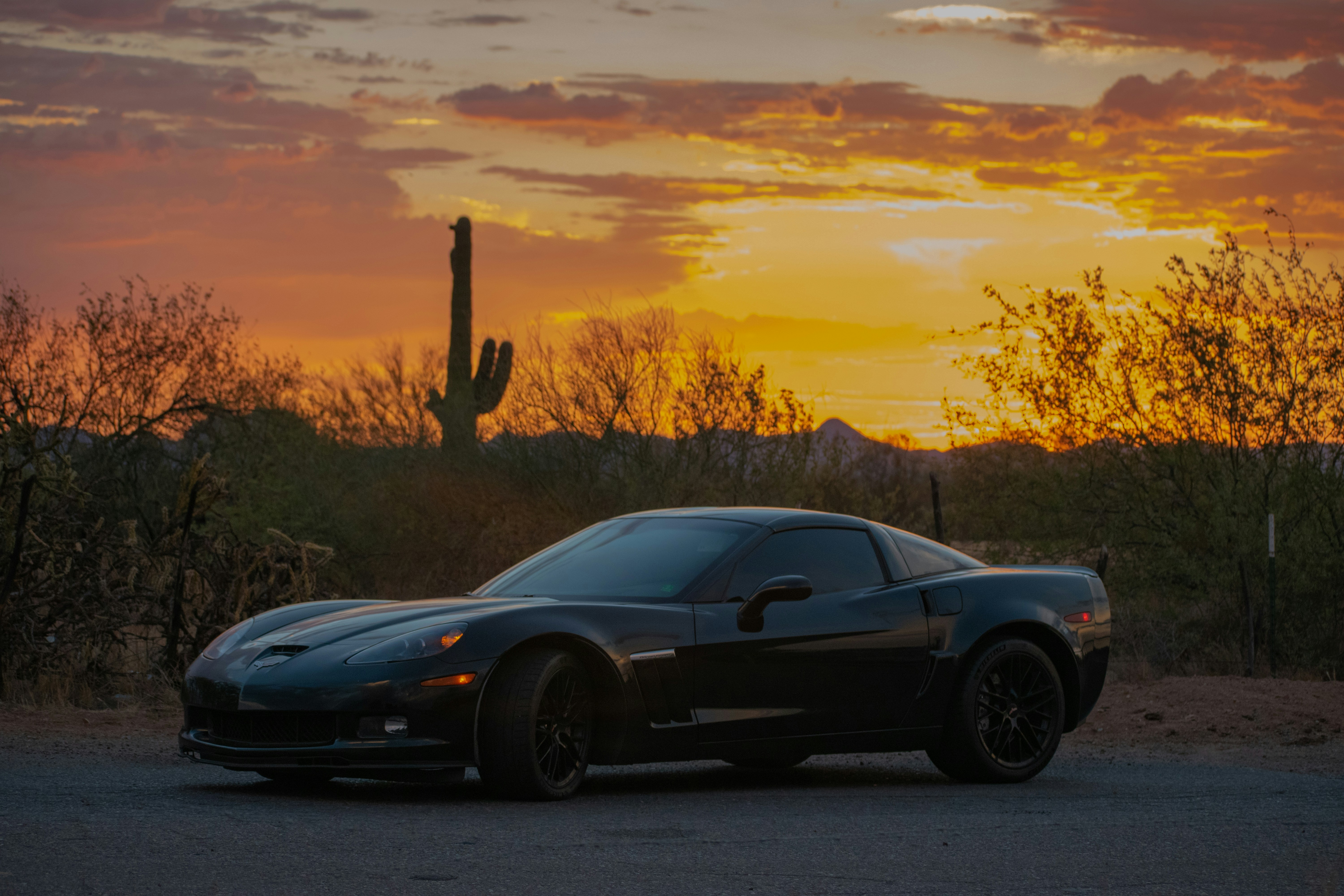 Desert dusk stance: a black sports car under a canyon sunset
