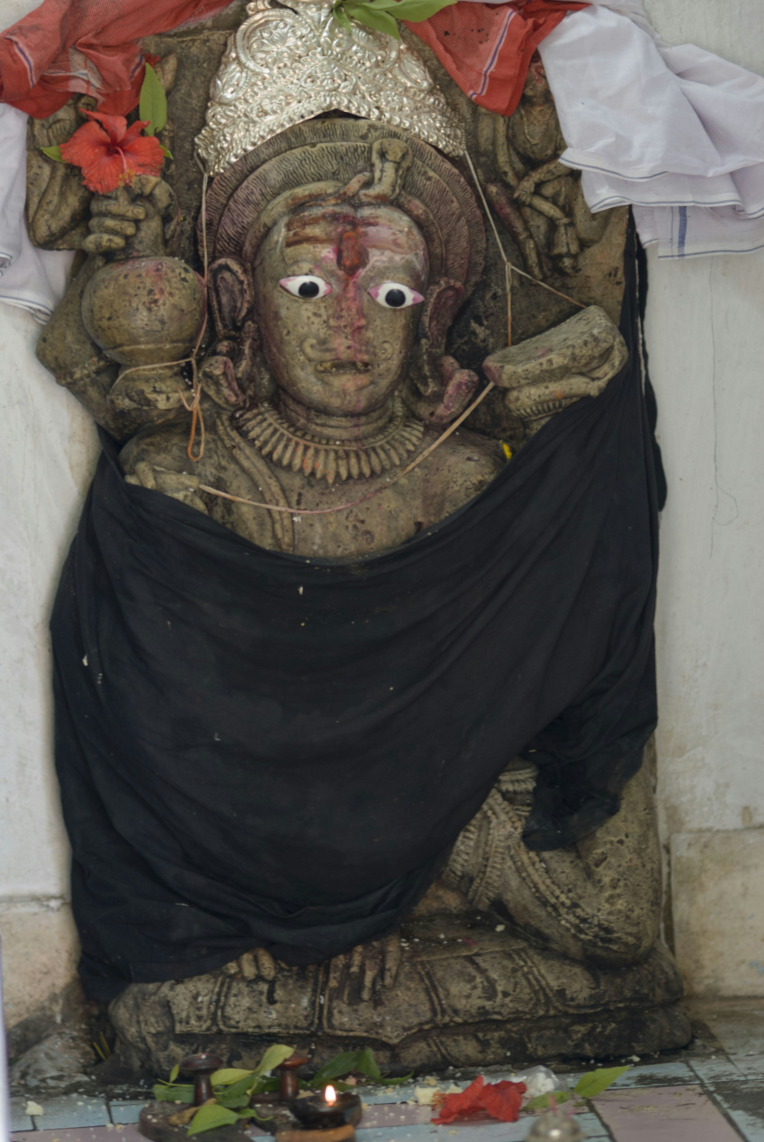 Ancient Sculpture Adorned with Ritual Offerings in a Shrine