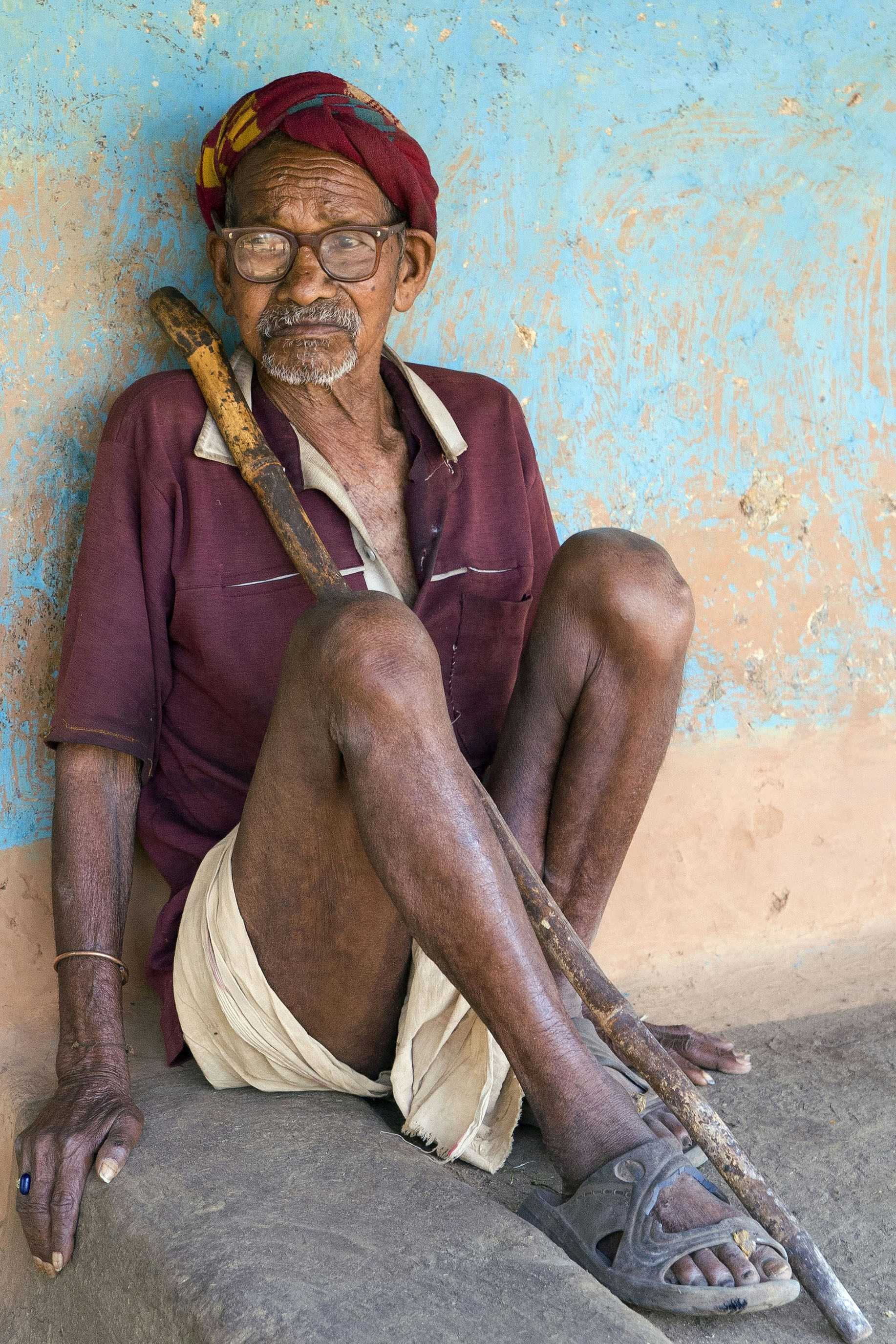 The Elder with a Cane: Quiet Strength by a Turquoise Wall
