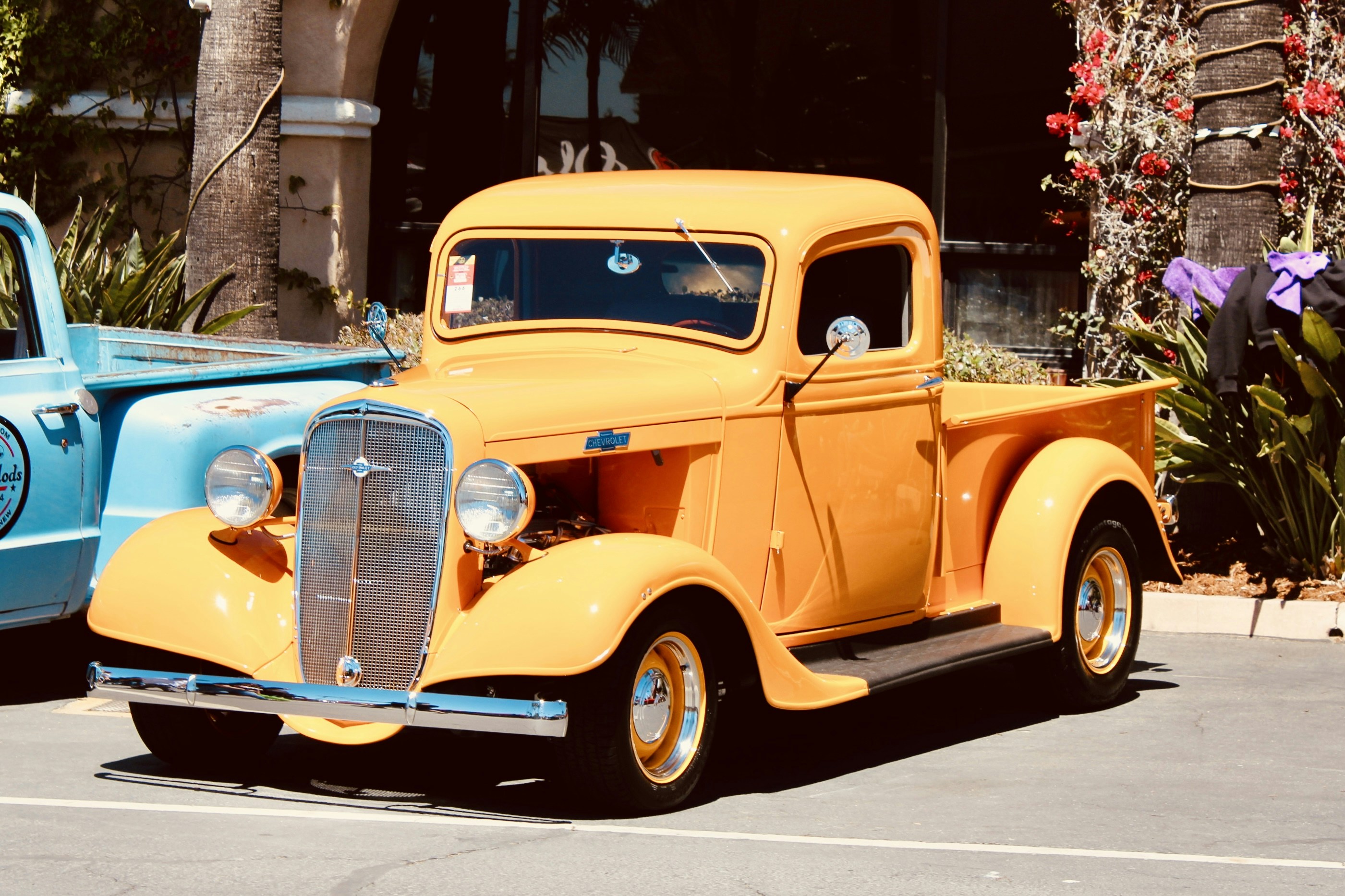 Sunlit Vintage: A Candy-orange Ford Pickup Halts in a Parking Lot Show