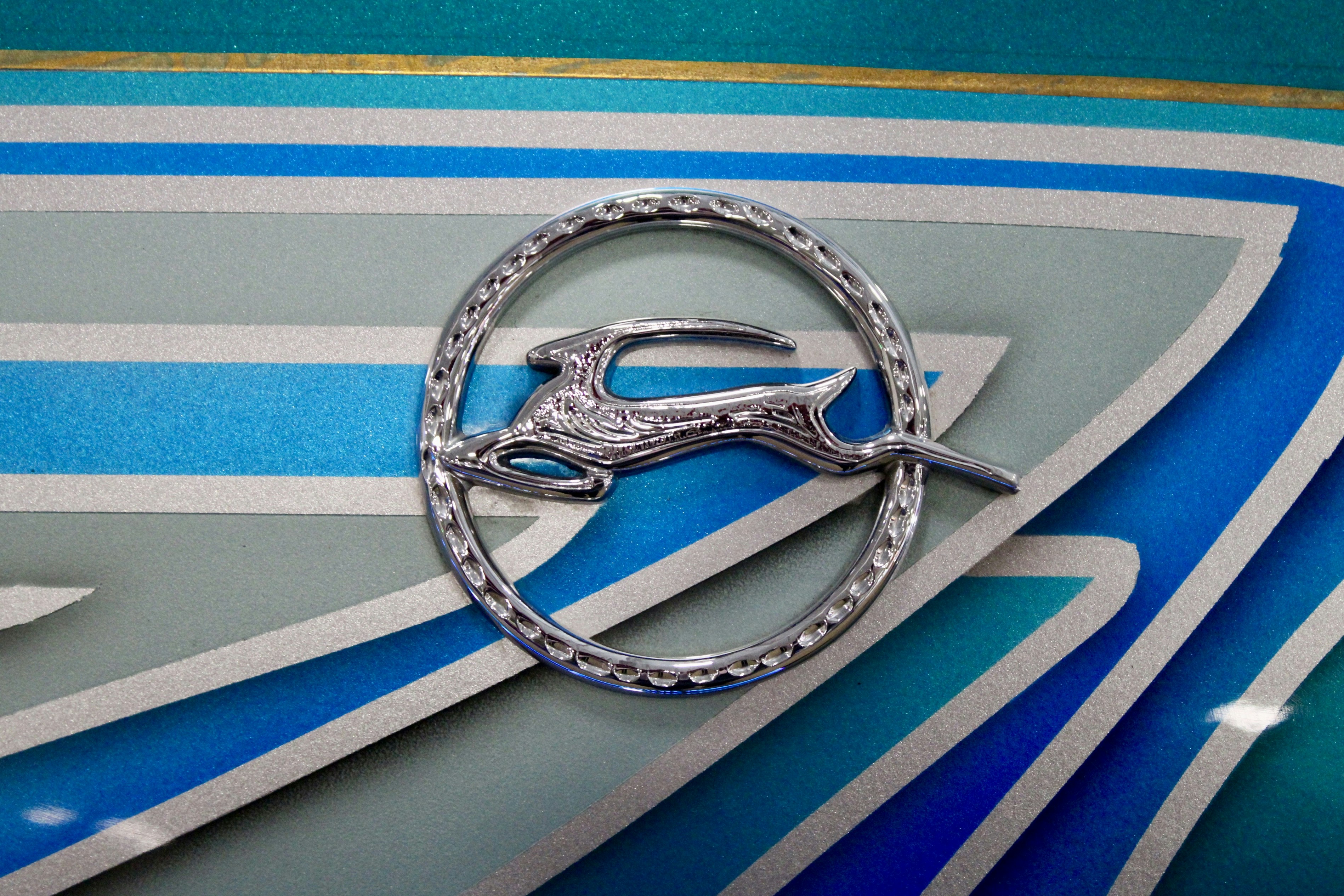 Metallic emblem resting on layered blue-green geometric pattern