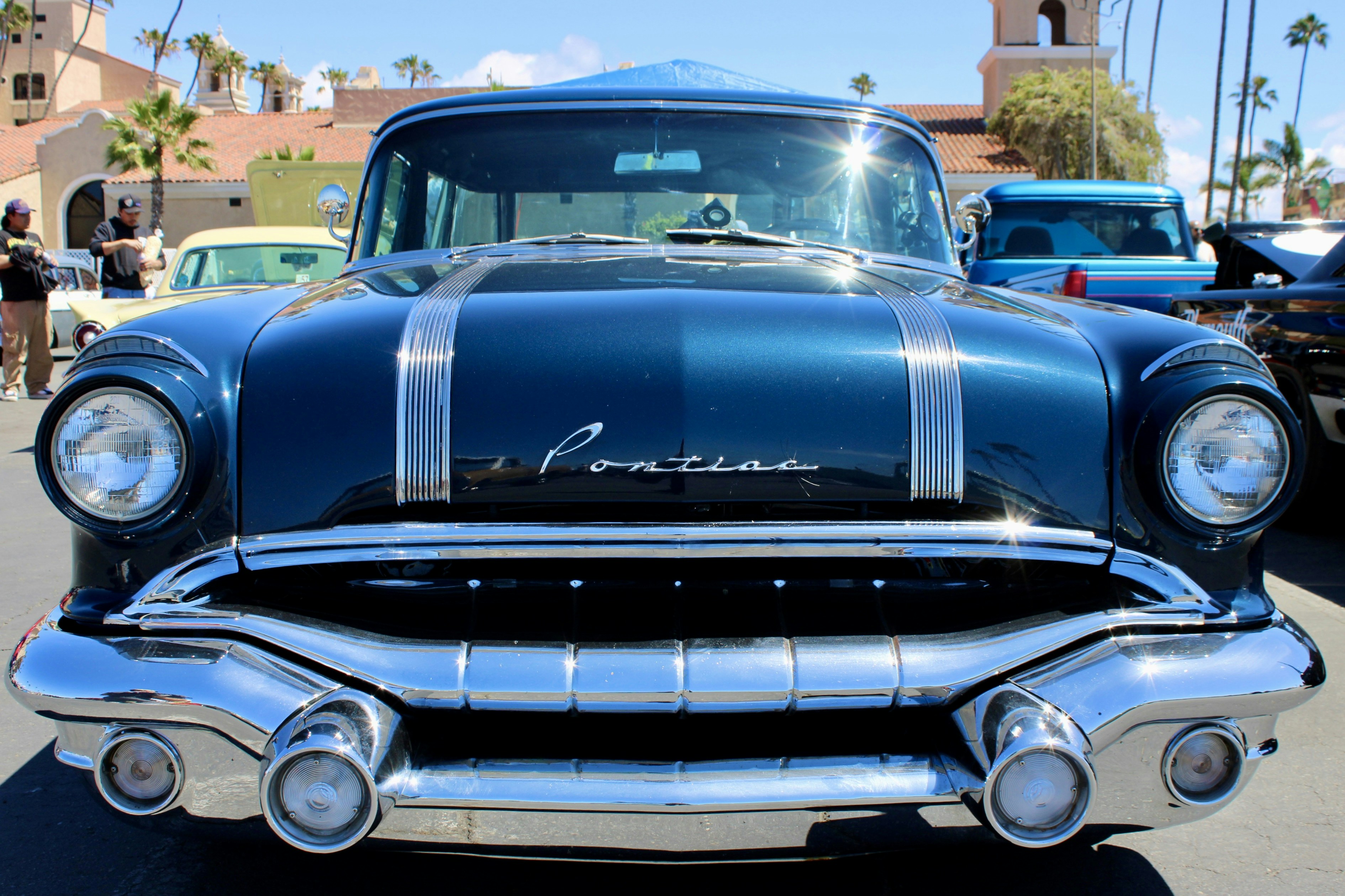 Chrome Crown: A Blue Classic Pontiac Grins Under Sun