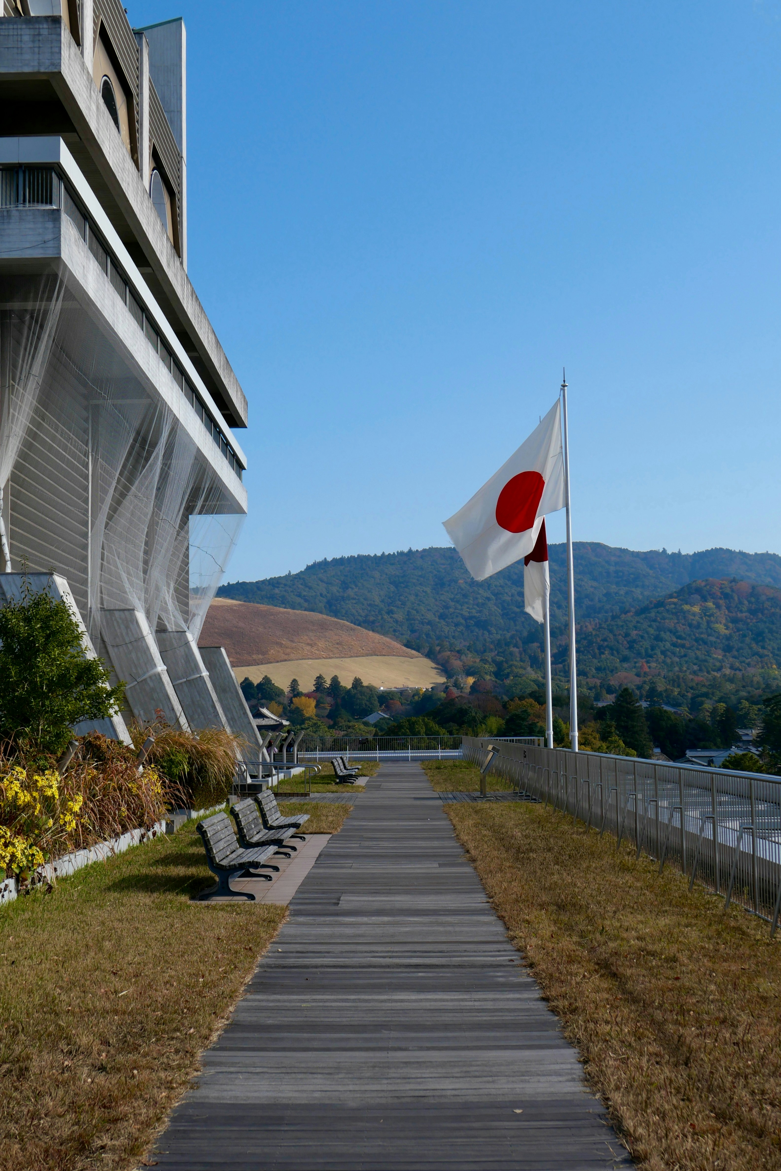 Flag over the hillside: a modern riverside promenade under a clear blue sky