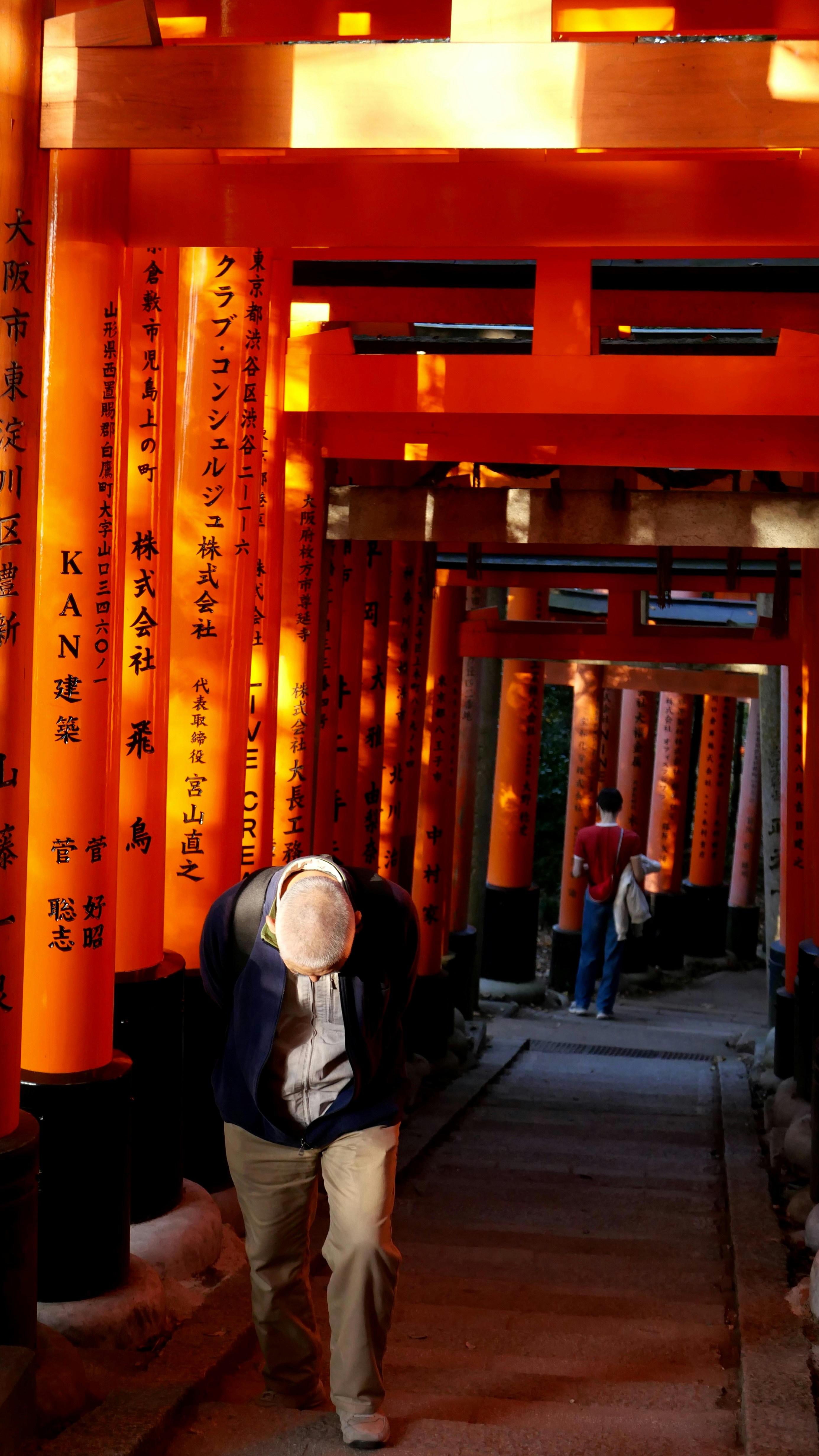 Red Gates, Quiet Step: A Visitor Bends Under a Sea of Torii