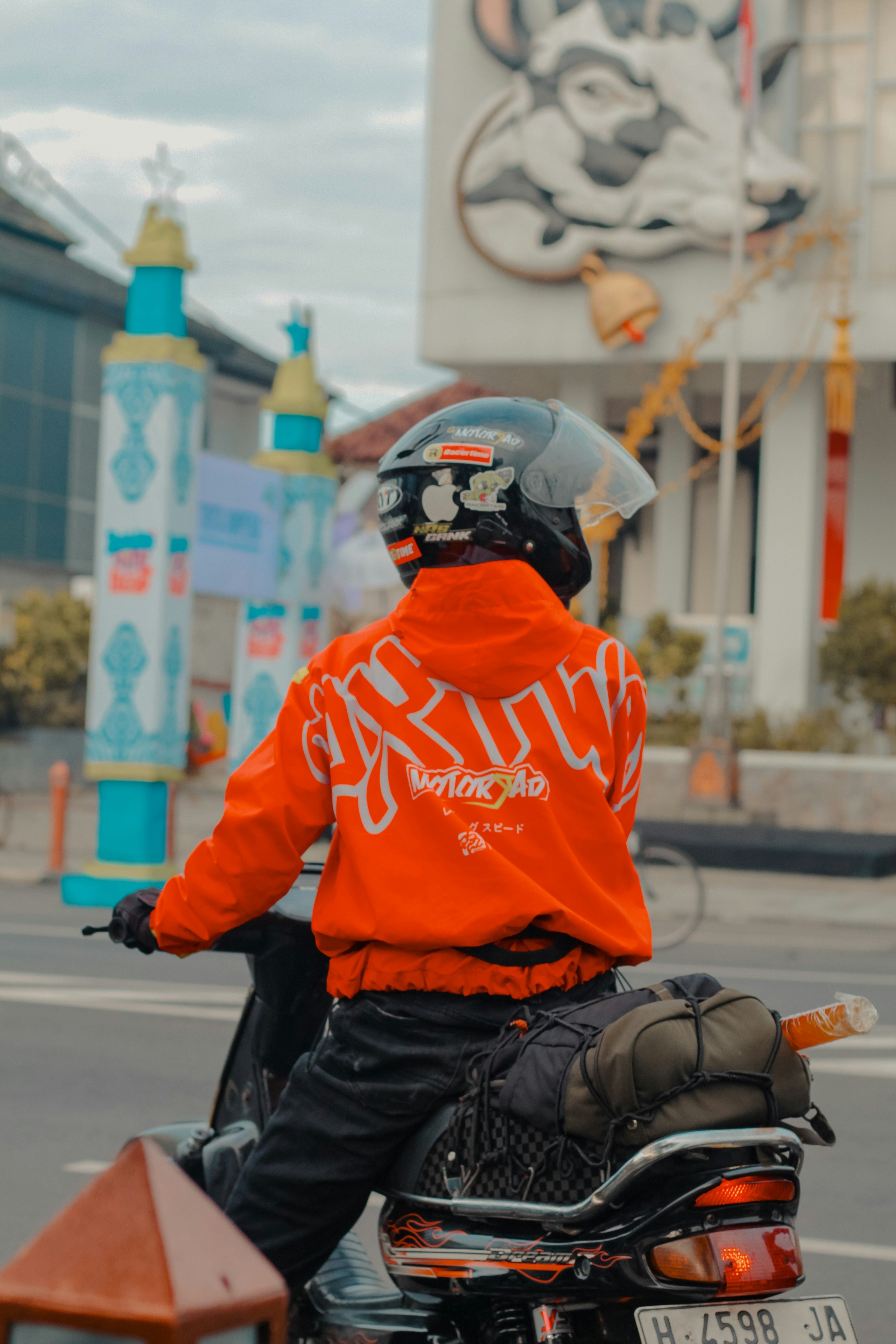 Orange hoodie rider paused at a colorful urban plaza