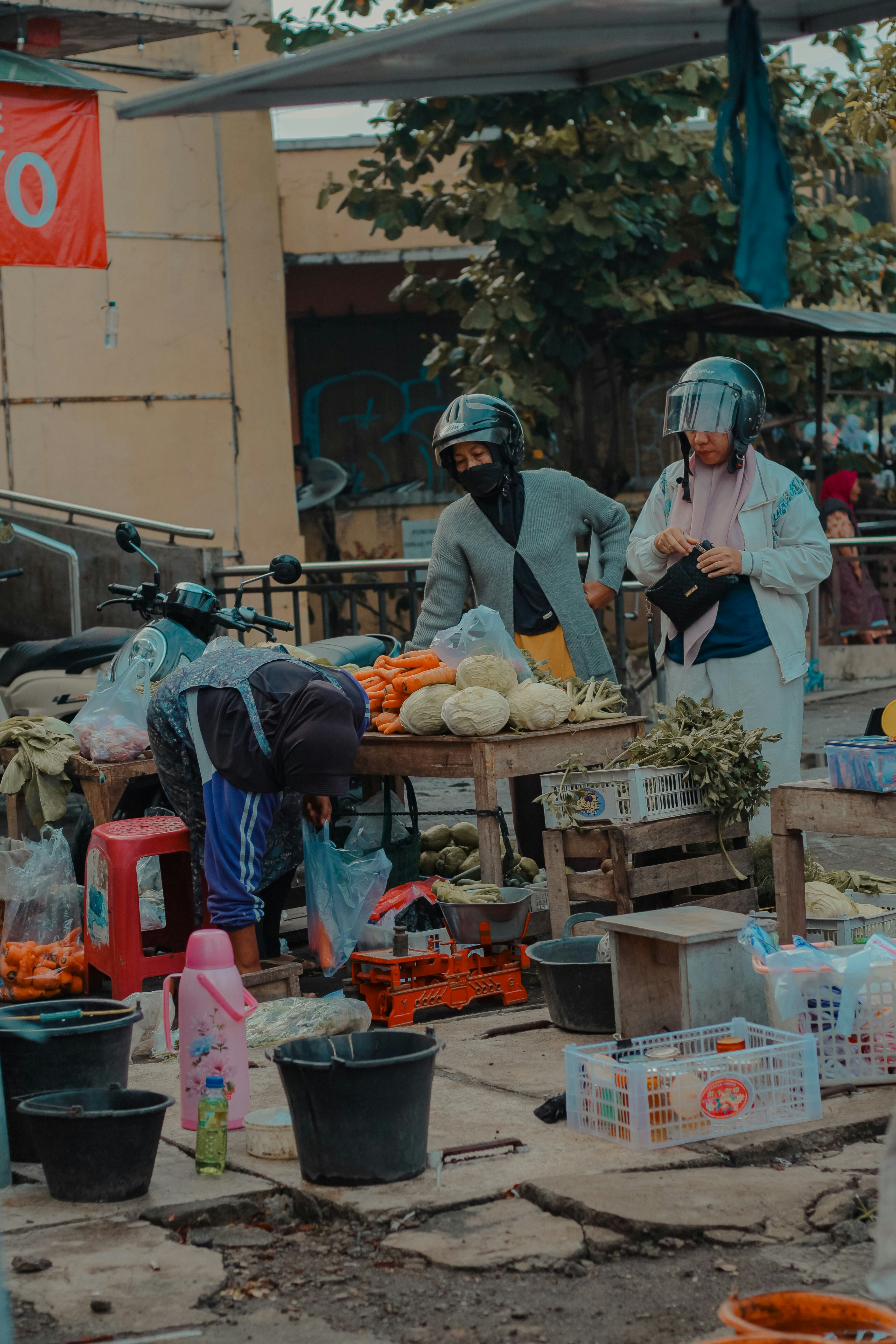 Market Stand at Dusk: Vendors and a Shopper in Helmet Amid Fresh Produce
