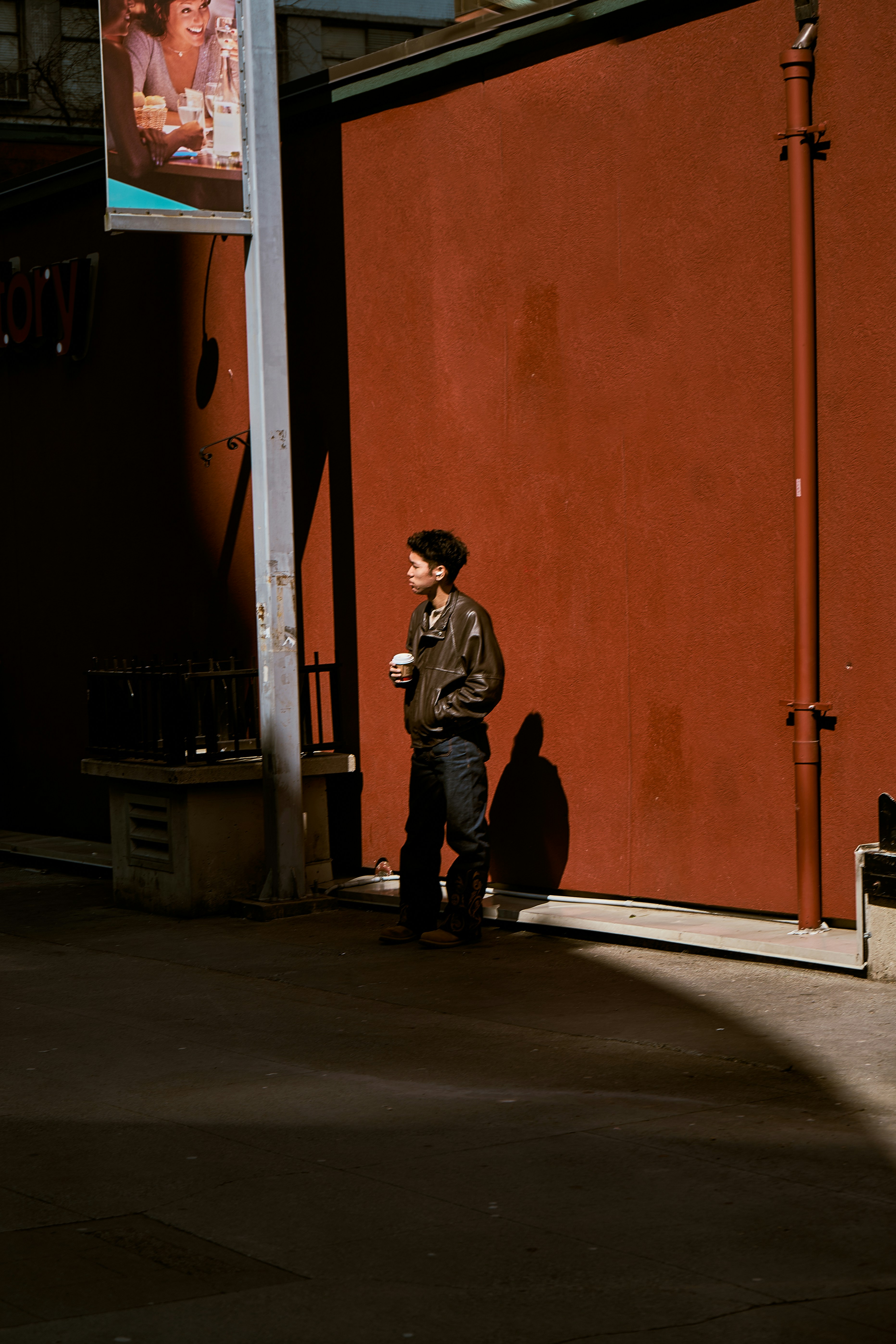 Streetlight Confession: A Man in Shadow by a Fiery Red Wall