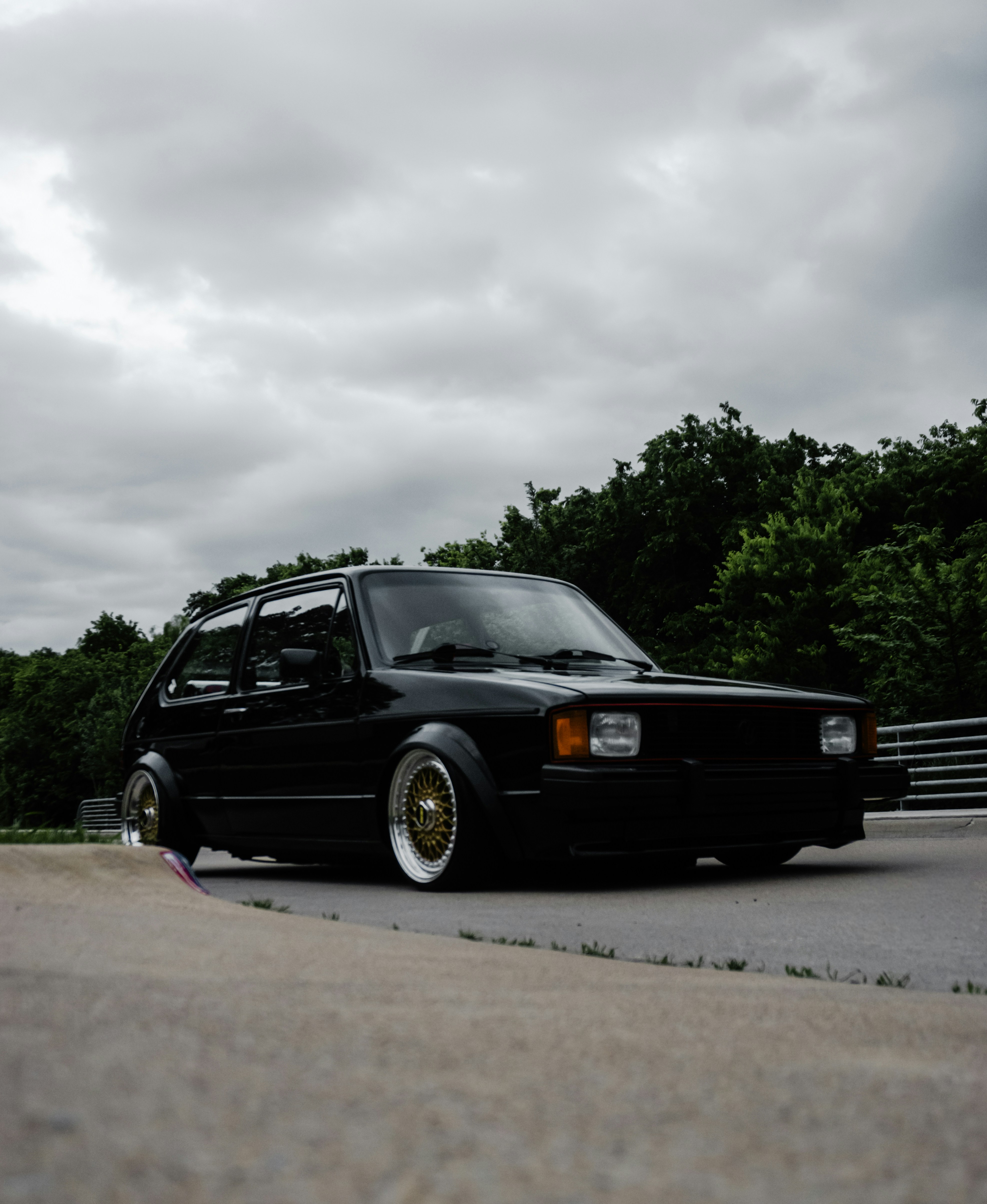 Low-slung Black Hatchback on a Curved Track with Overcast Sky