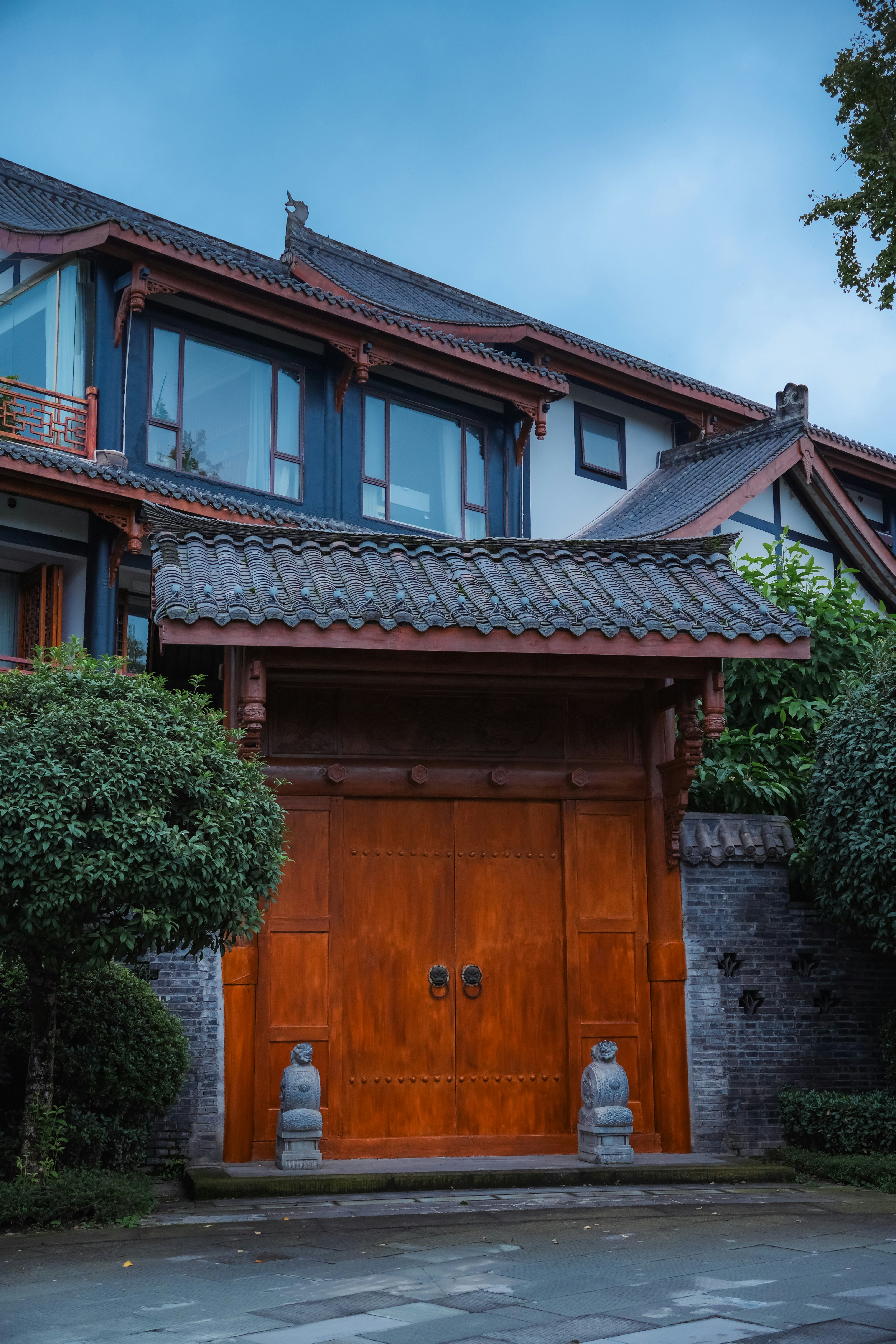Ceremonial wooden gate framed by traditional tiled roof and manicured hedges