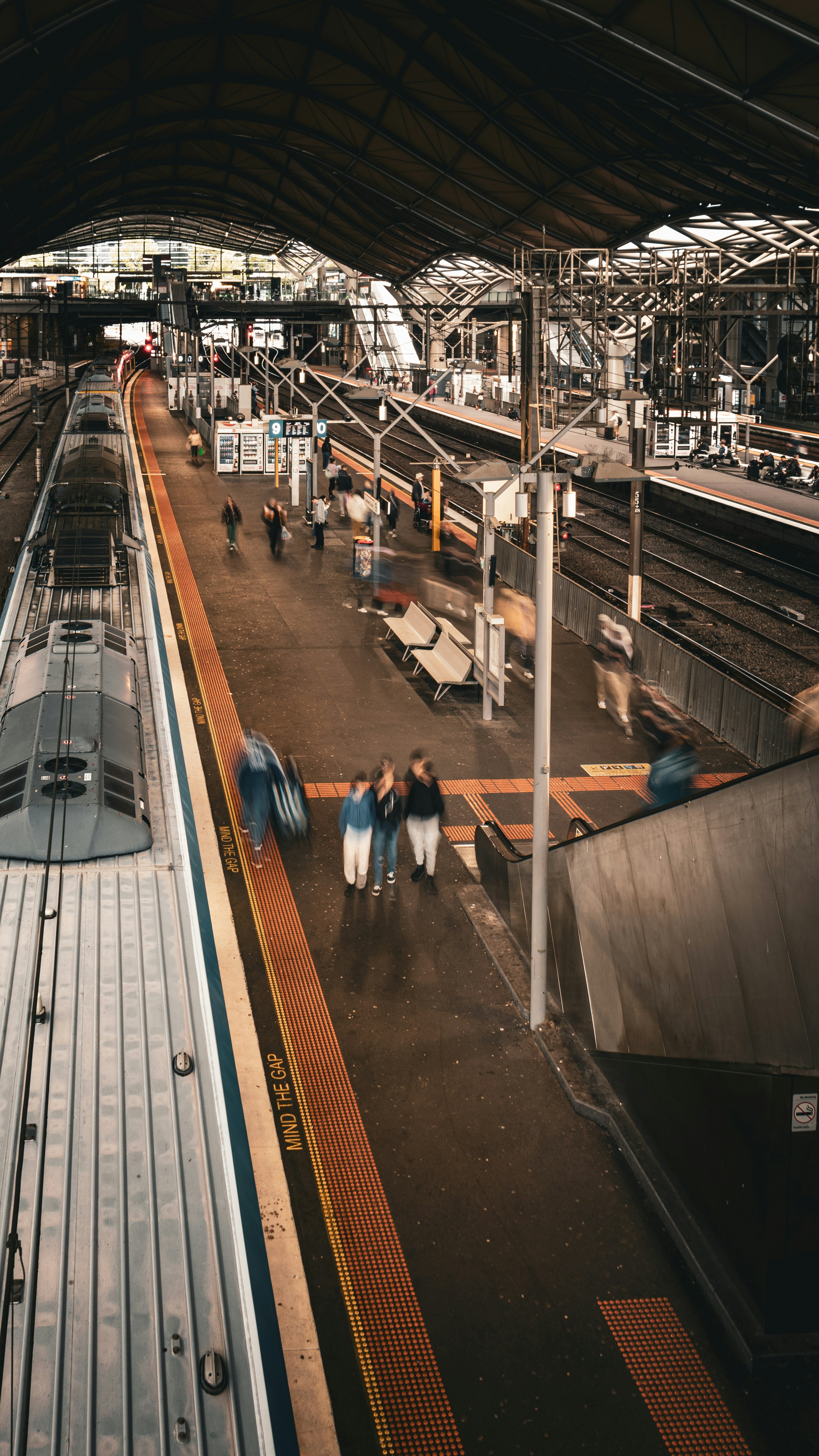 Midday Stroll on a Moving Platform: Commuters Blur Amidst Steel and Glass