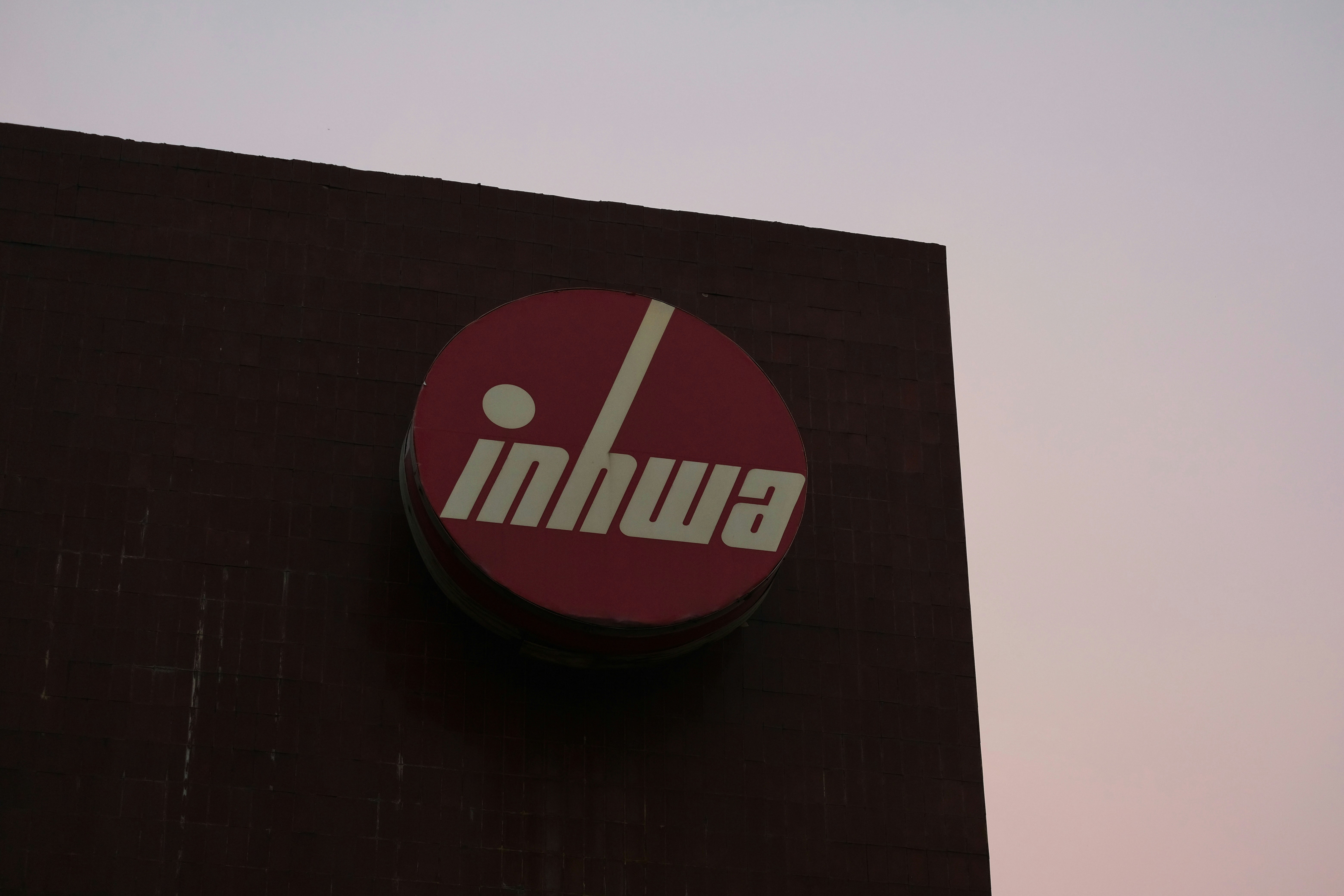 Circular Inhwa Sign Anchored Against a Silent Urban Wall