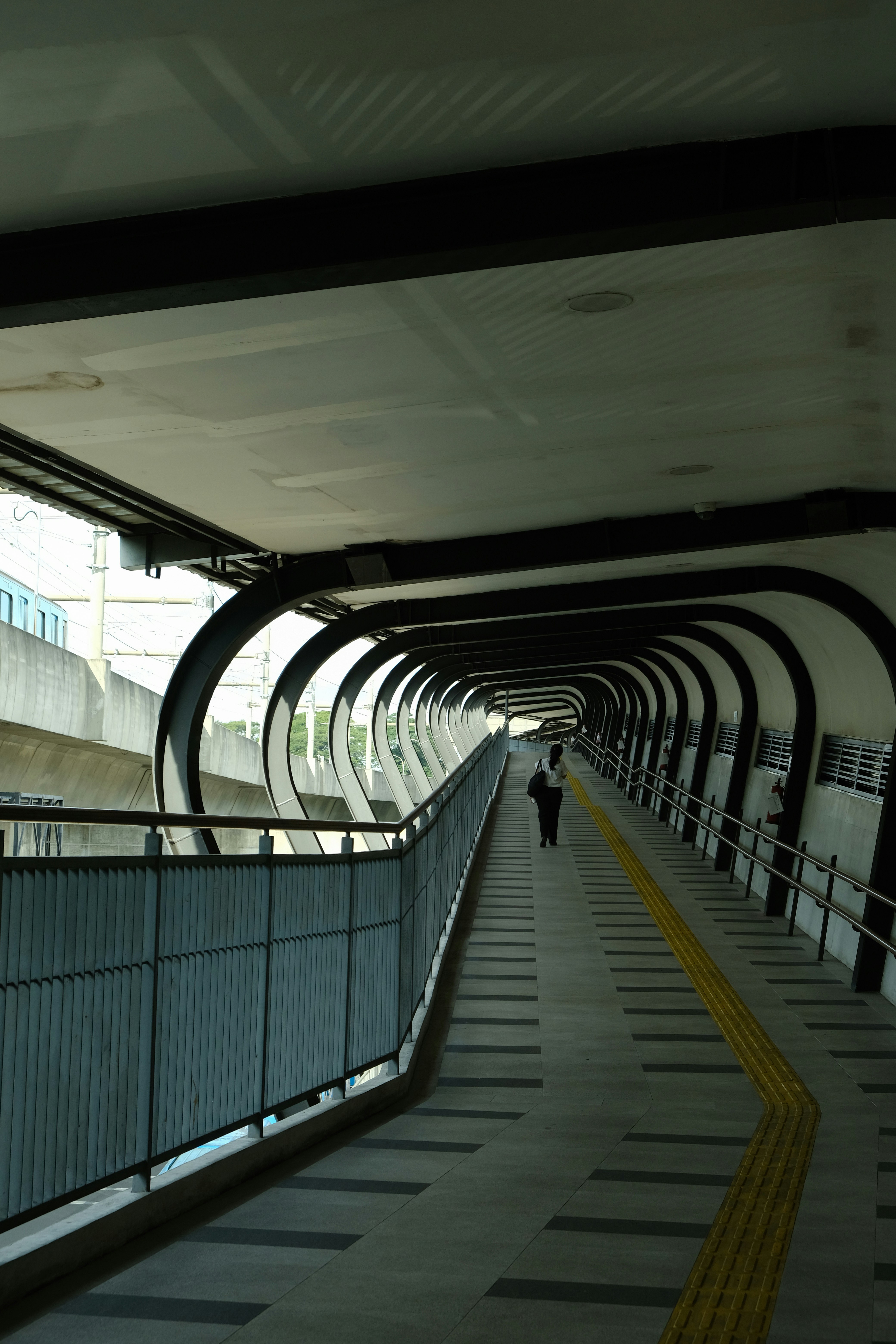 Tunnel of Echoes: A lone commuter strides through the curved walkway