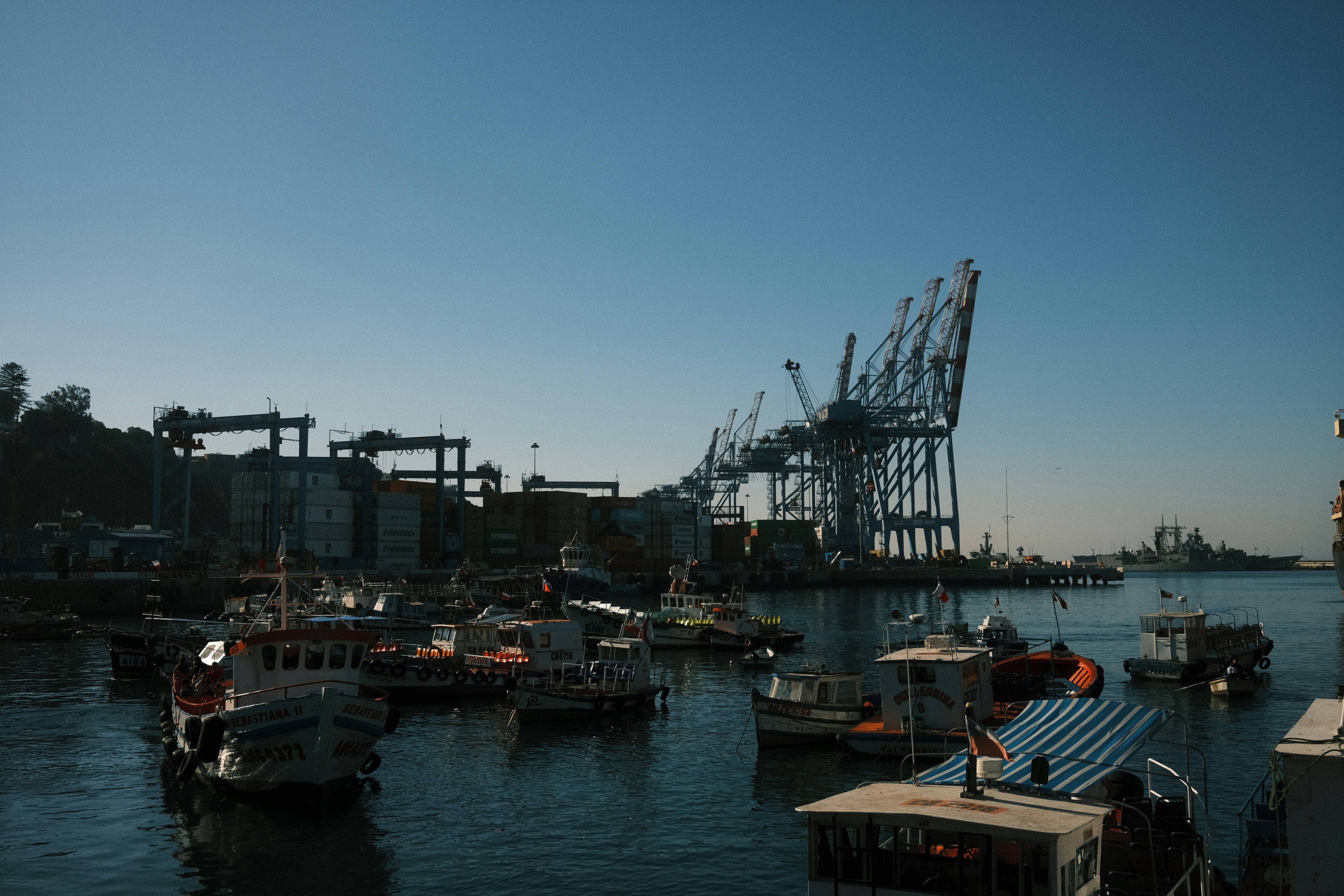 Harbor at Dusk: Docked Boats and Crane Skyline