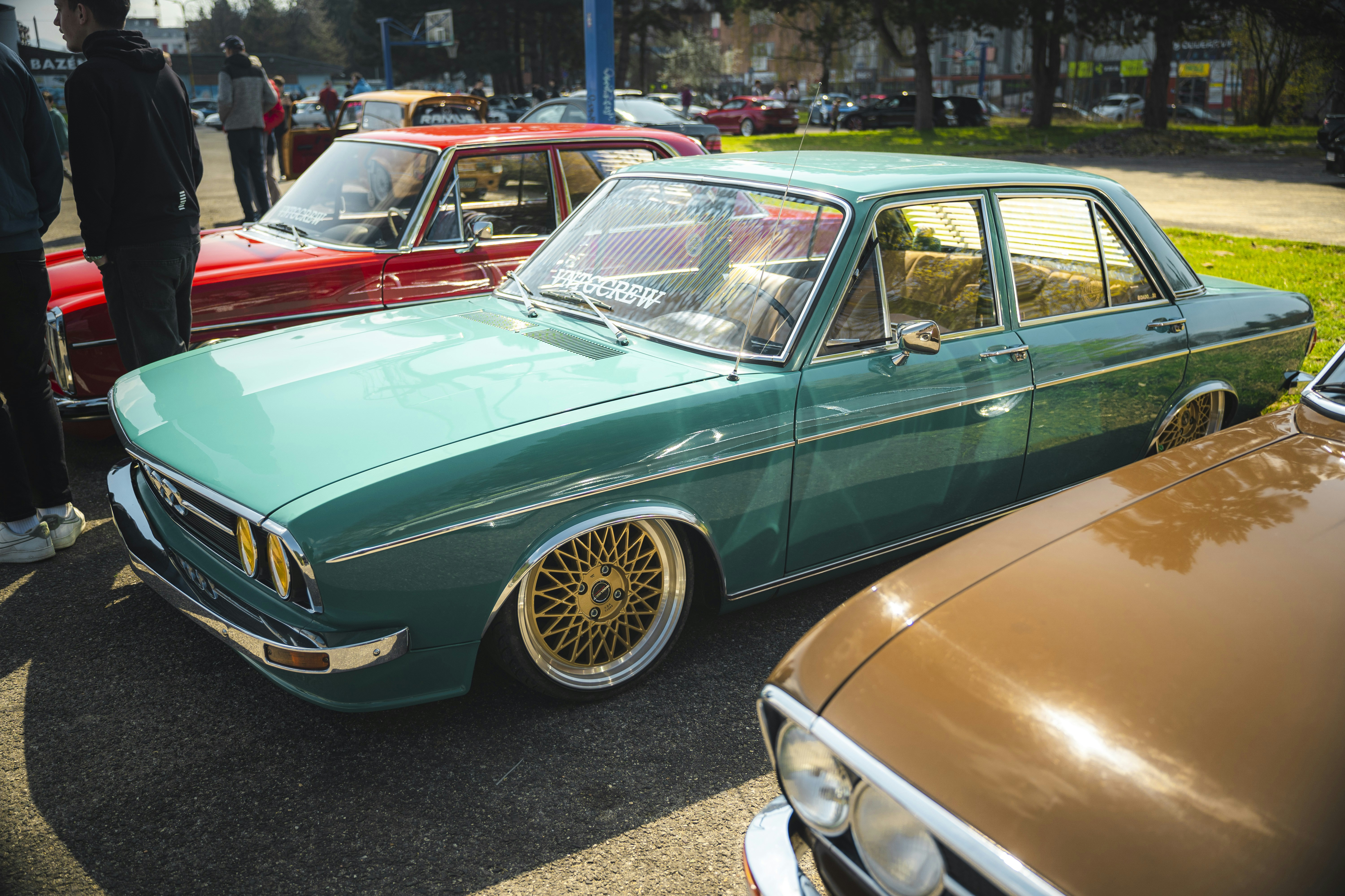 Emerald Glide: A teal classic sedan at a sunlit car show
