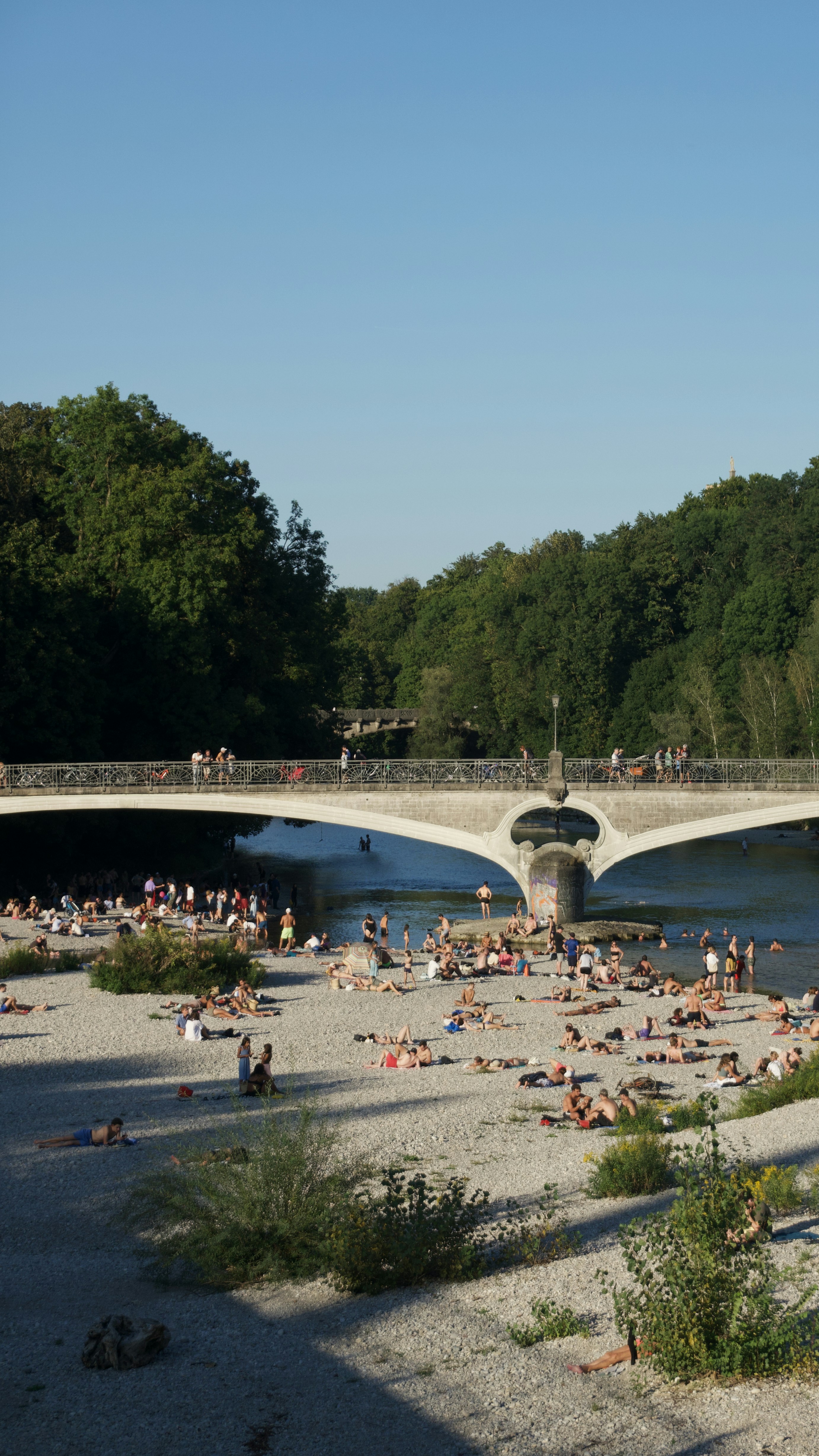 Sunlit Riverside Crowd Under a Historic Arch