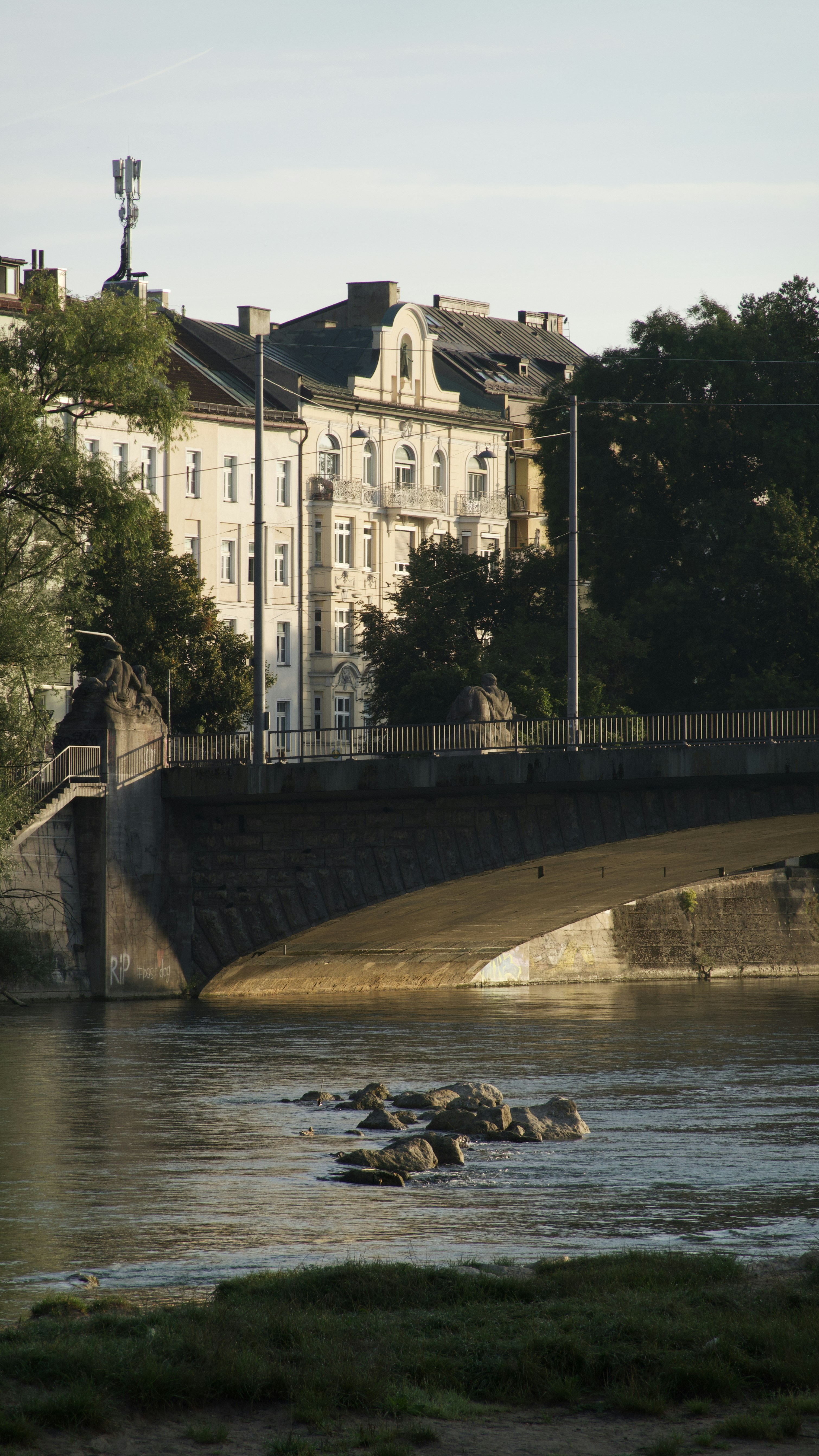 Stone bridge over a river with buildings beyond.
