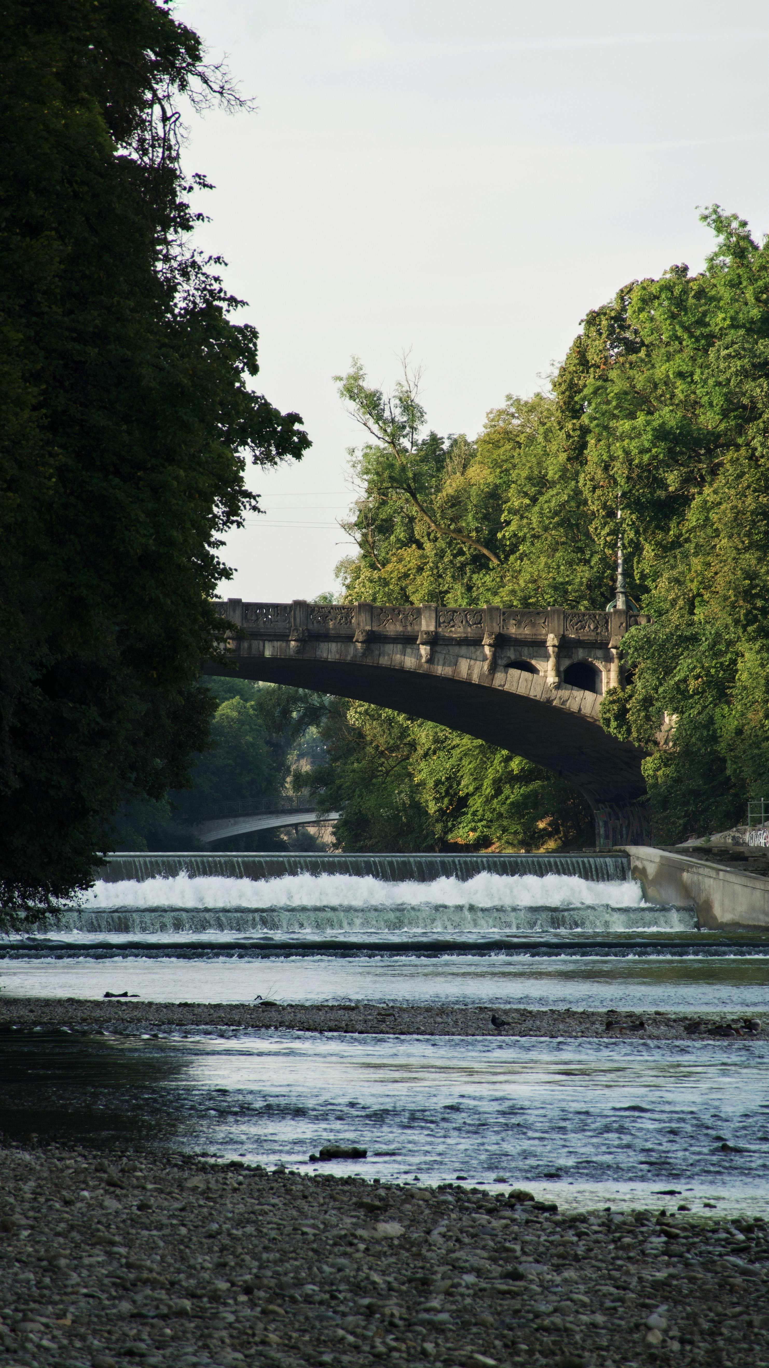 Arched Bridge Over a Quiet River: A Green Corridor Beneath Sky