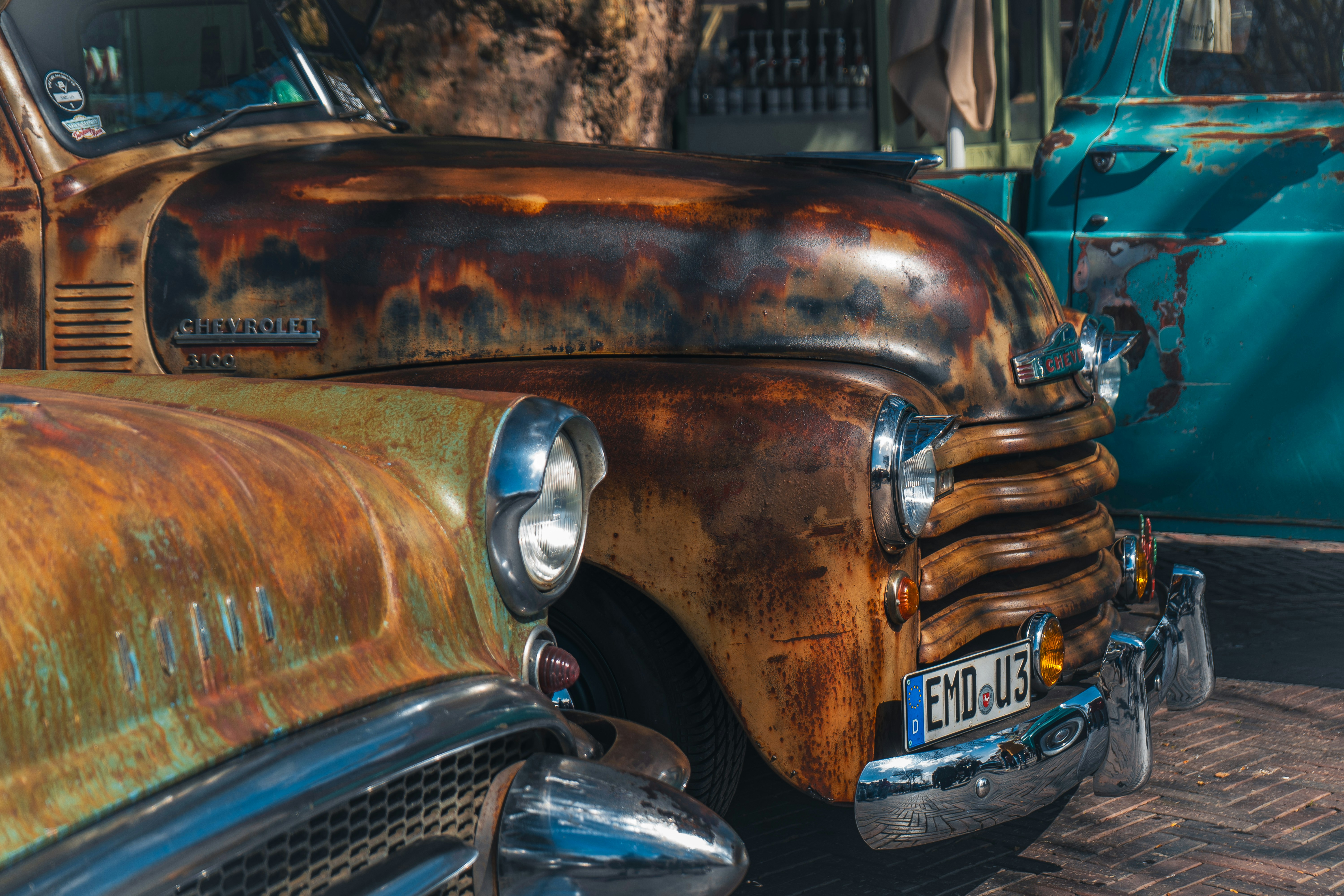 Rust and Chrome: A Pair of Timeworn Trucks Resting by the Courtyard