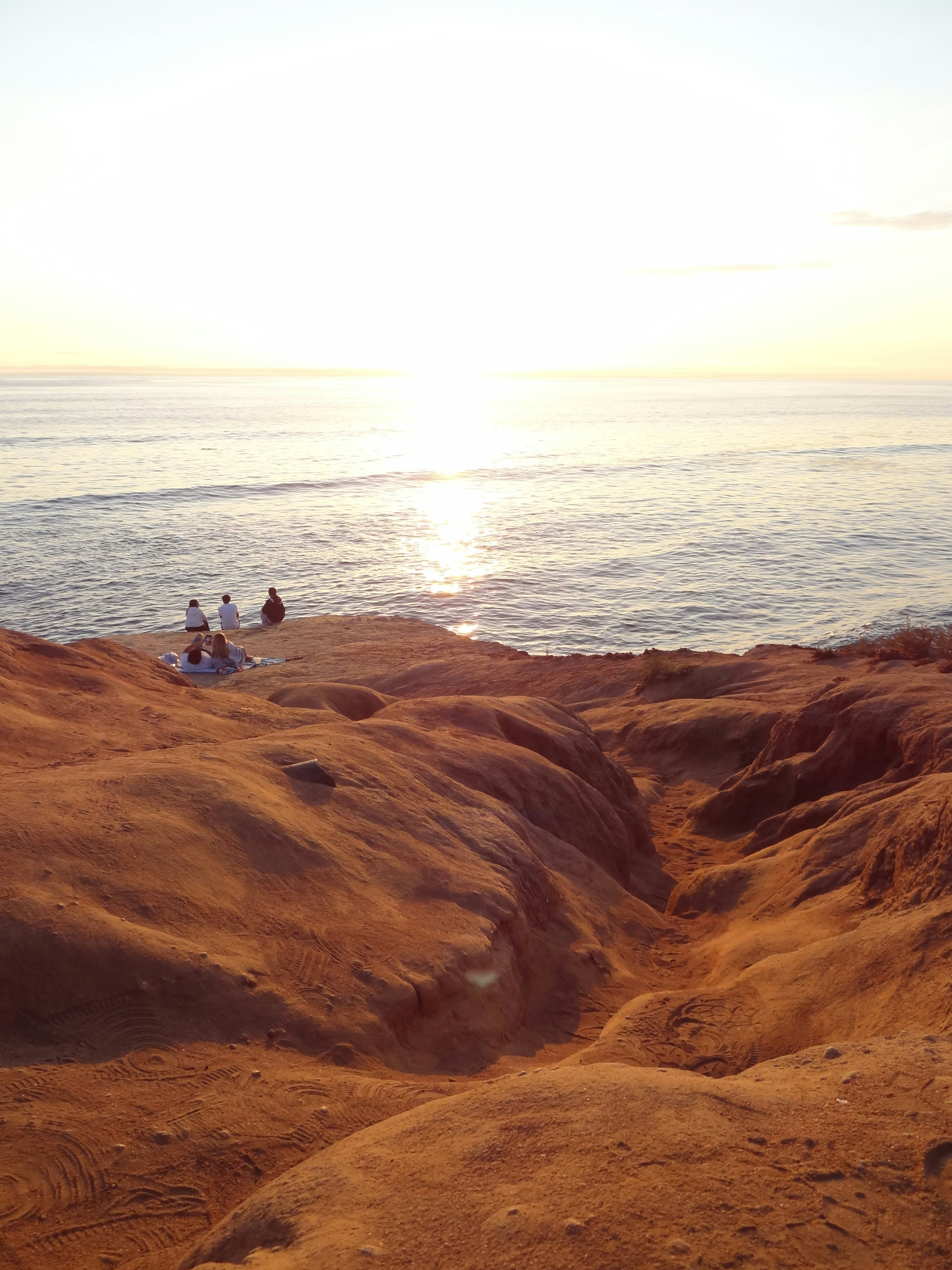 Sunlit Cliffs at Dusk: People Silhouetted Above the Sea