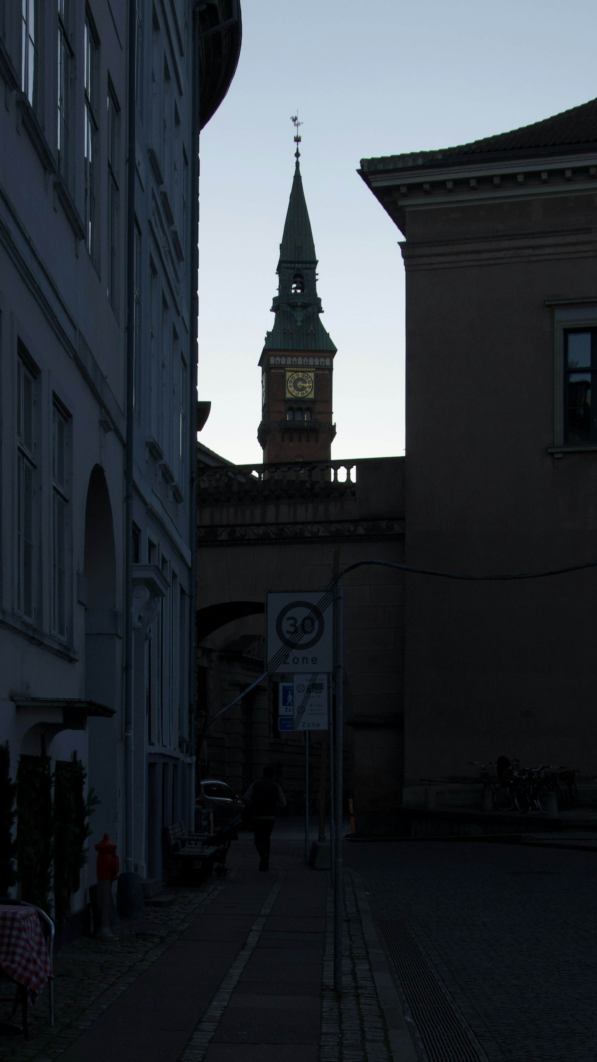 Clock Tower Rising Over Narrow Cobblestone Street