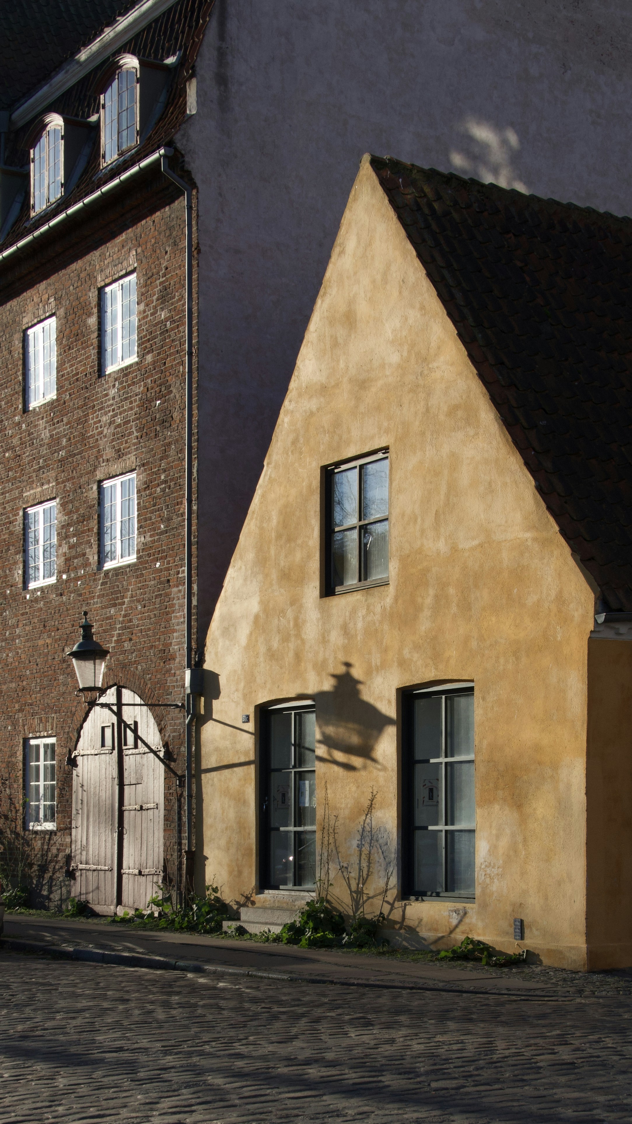 Sunlit yellow house and shadowed doorway on a cobblestone street