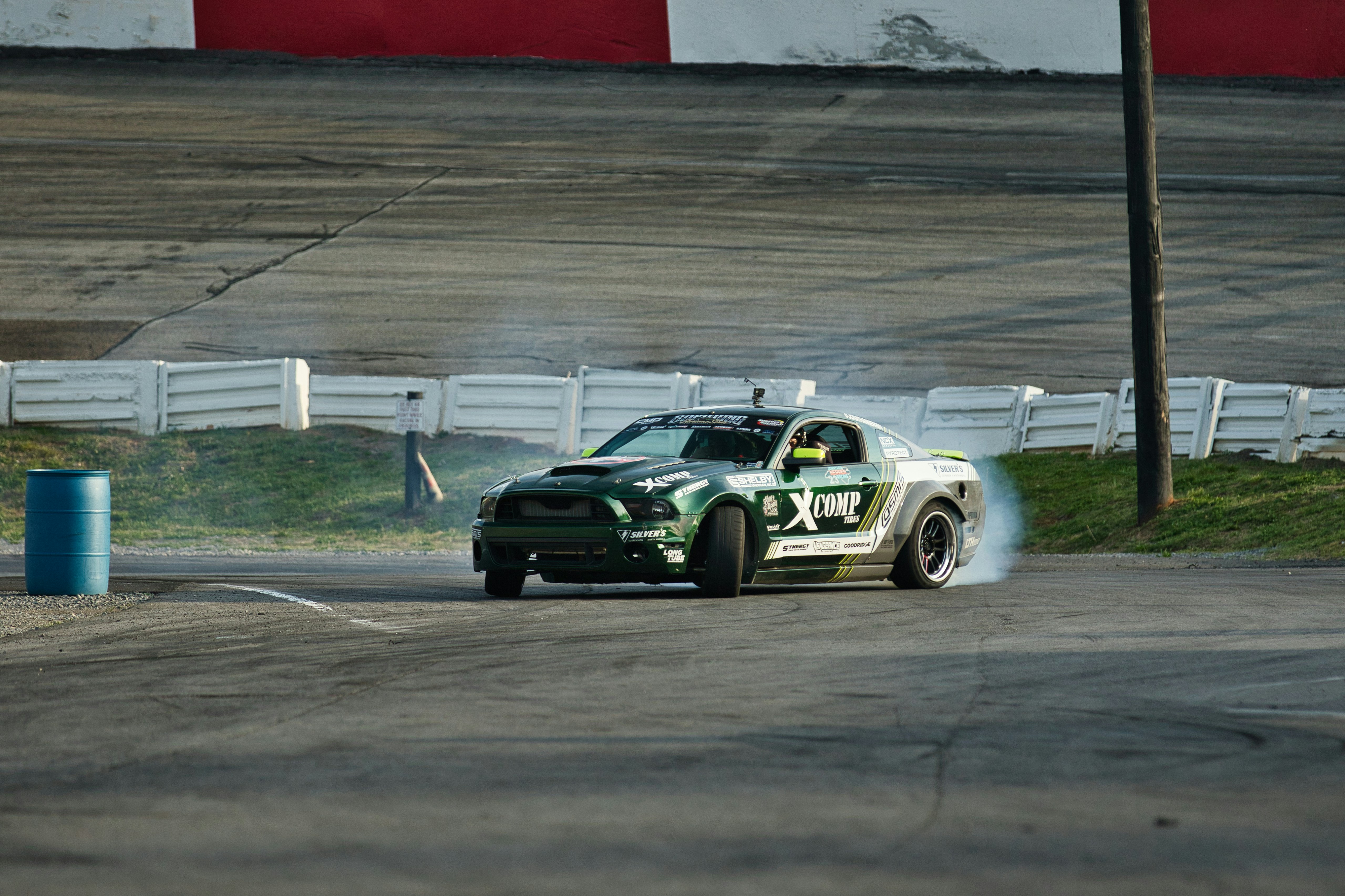 Green Race Car Slices Through a Barrier of Concrete at the Track