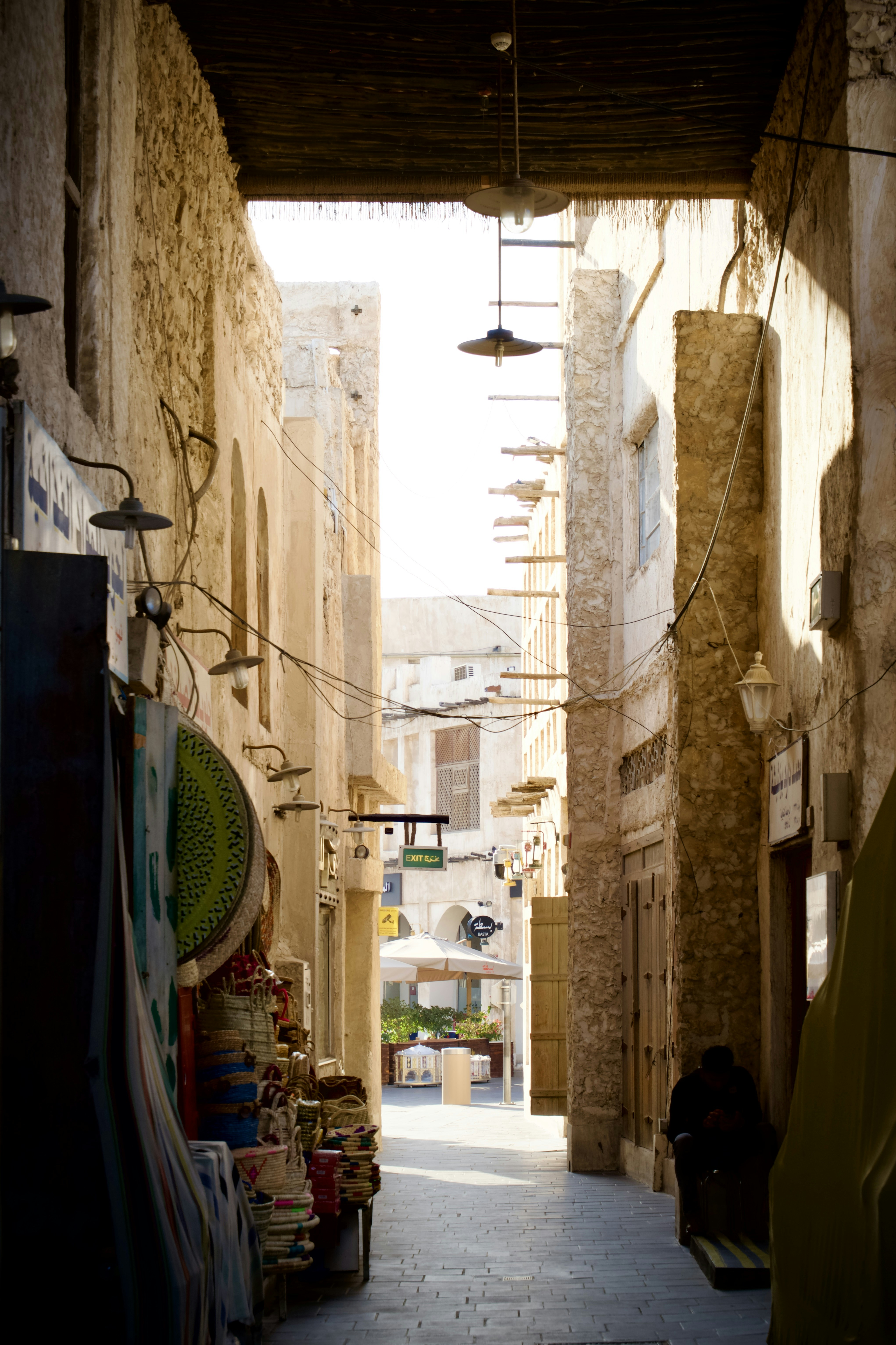 Sunlit Alleyway Through Stone Archway with Market Stalls
