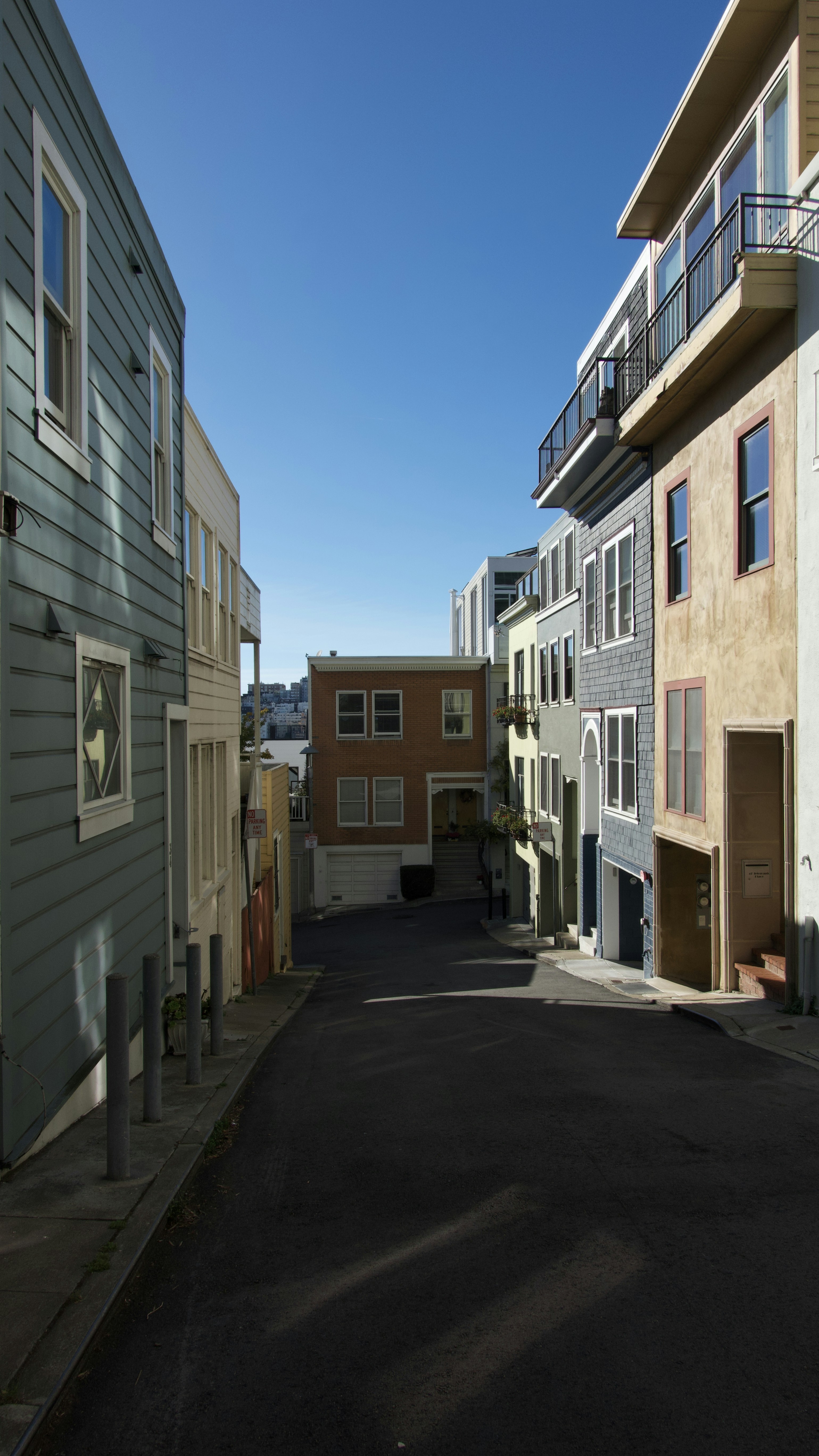 Narrow street between colorful buildings under a clear blue sky.