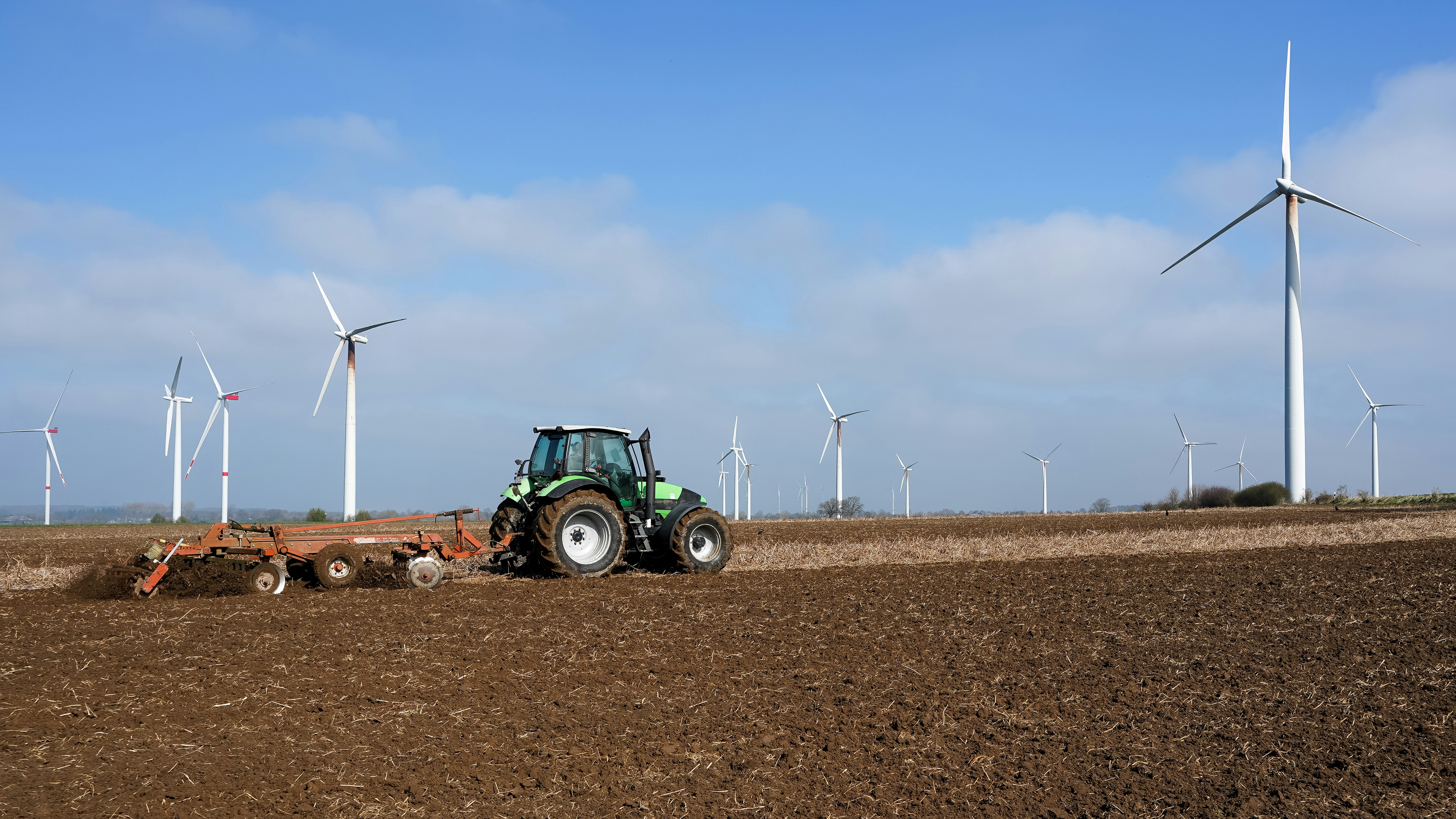 Tractor at Work Beneath a Sea of Wind Turbines