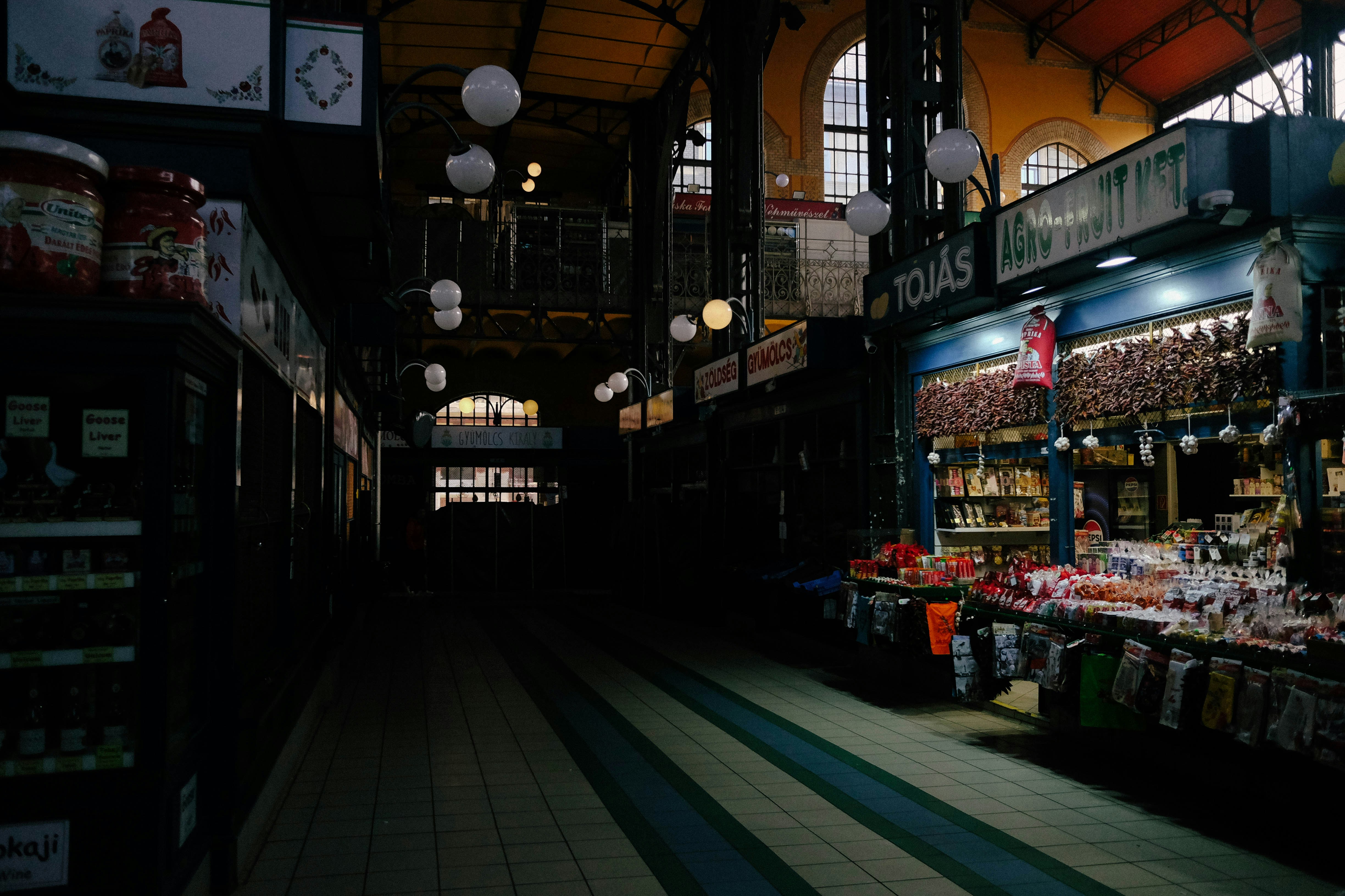 Dim Market Corridor with Grocery Stalls under Arched Ceiling