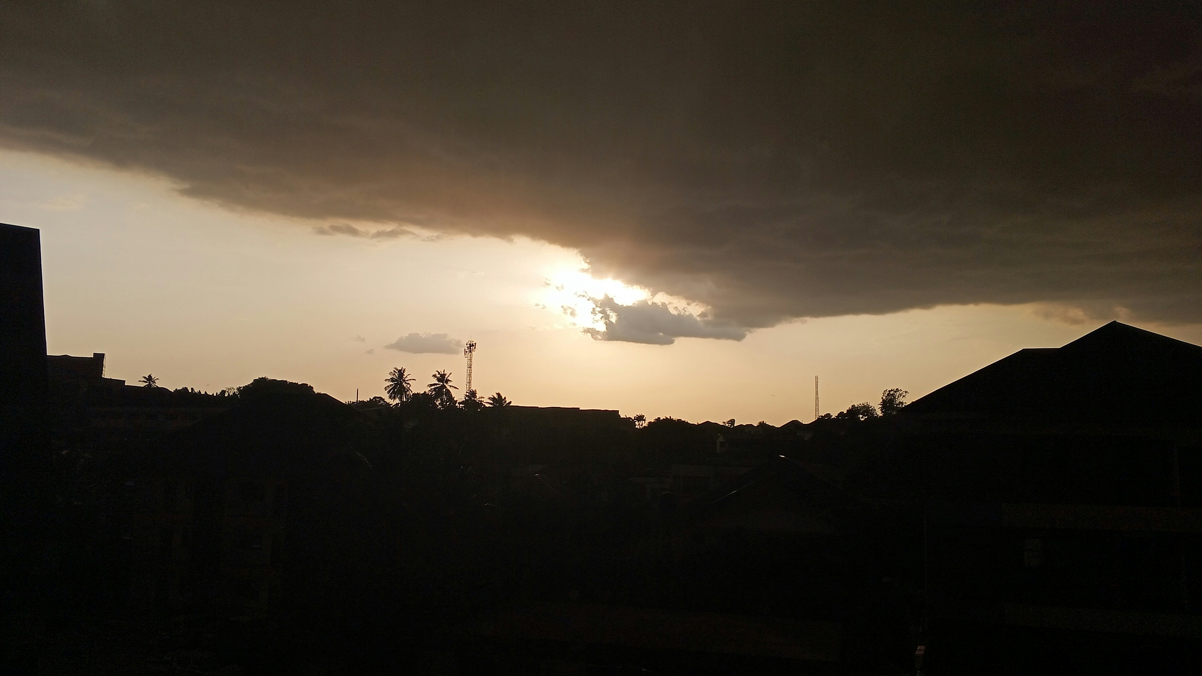 Sunset behind dark clouds over silhouetted buildings