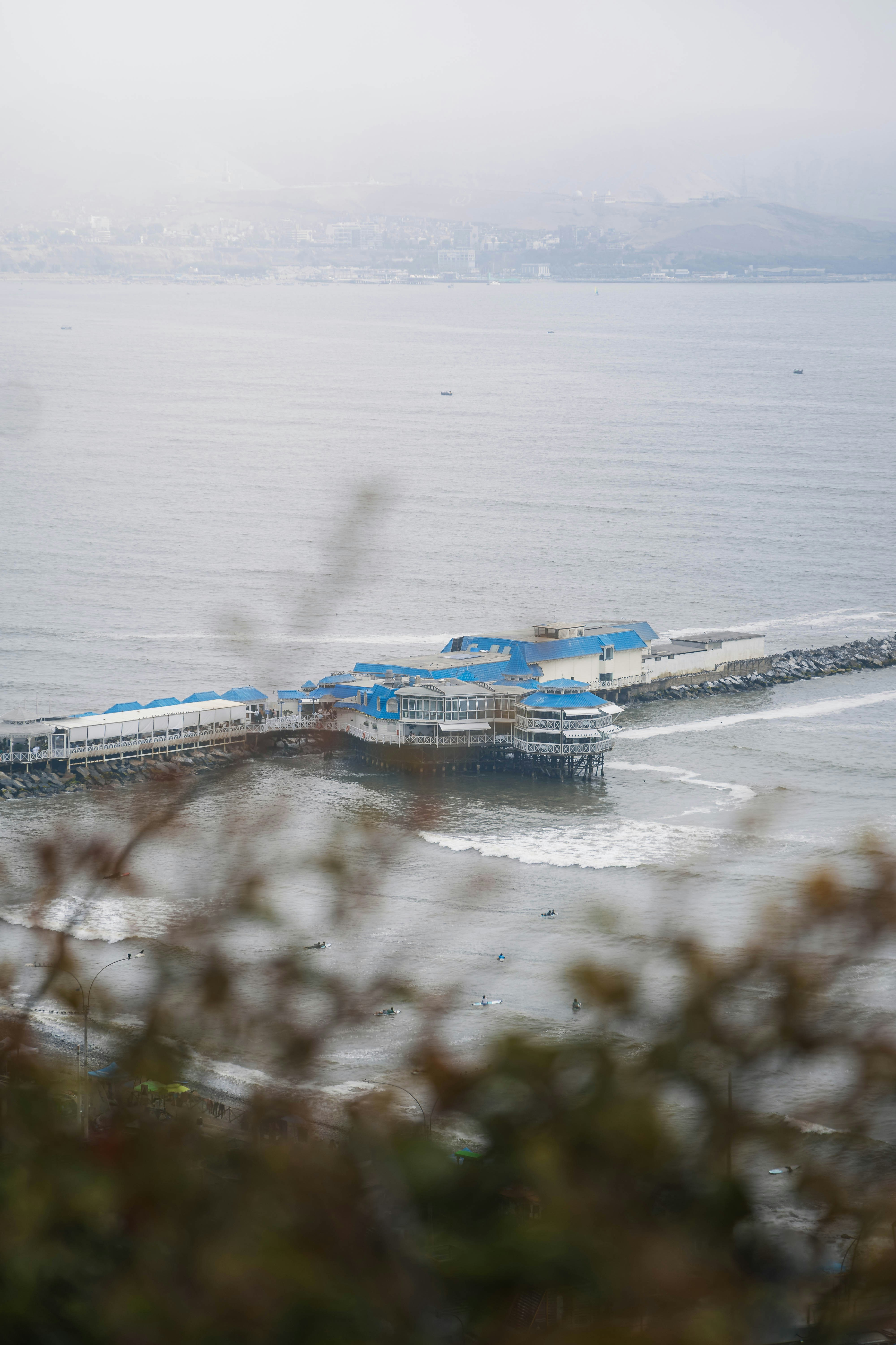 Blue-roofed pier stretching into a misty bay