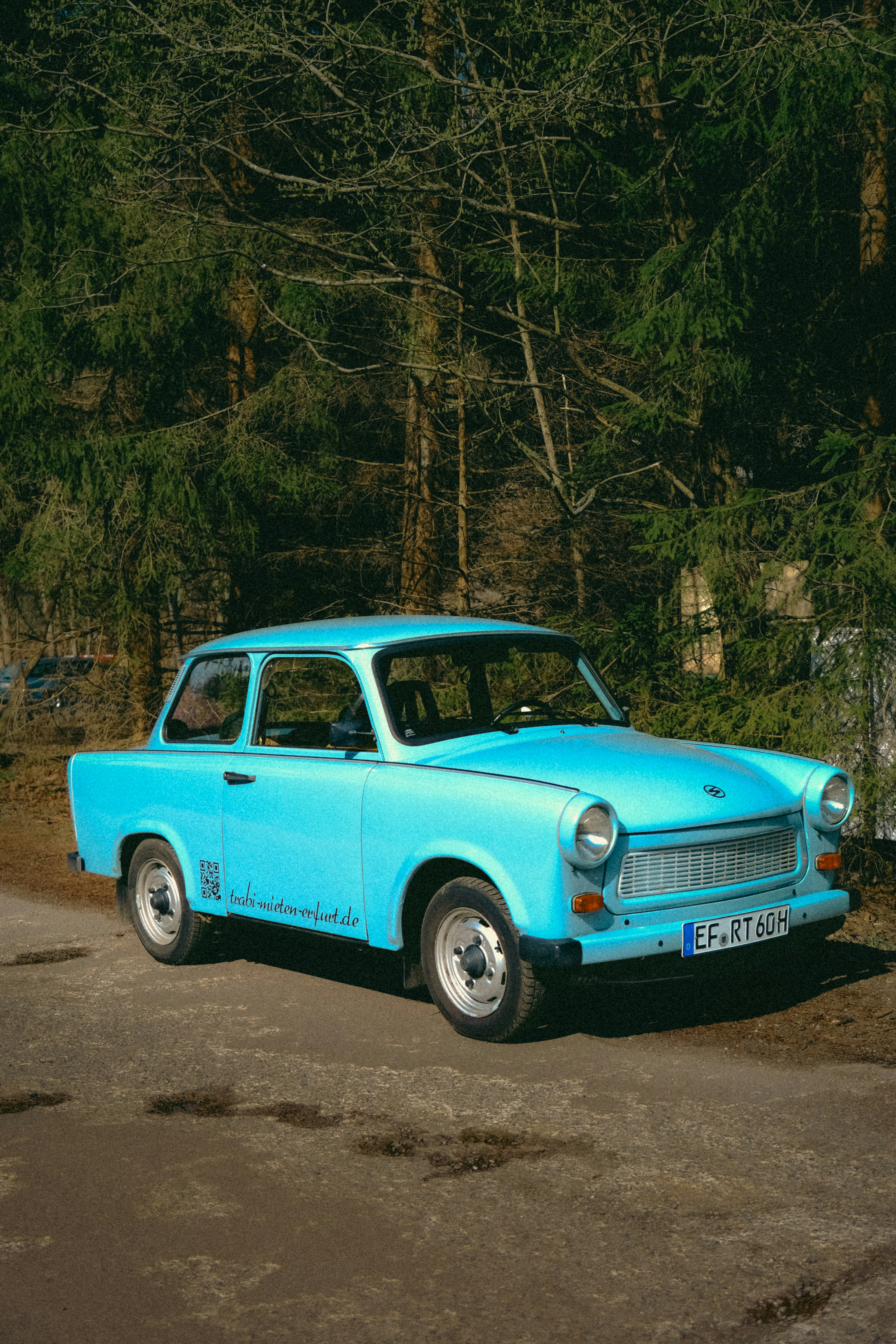 Azure Classic: a vintage blue Trabant resting by a forest road