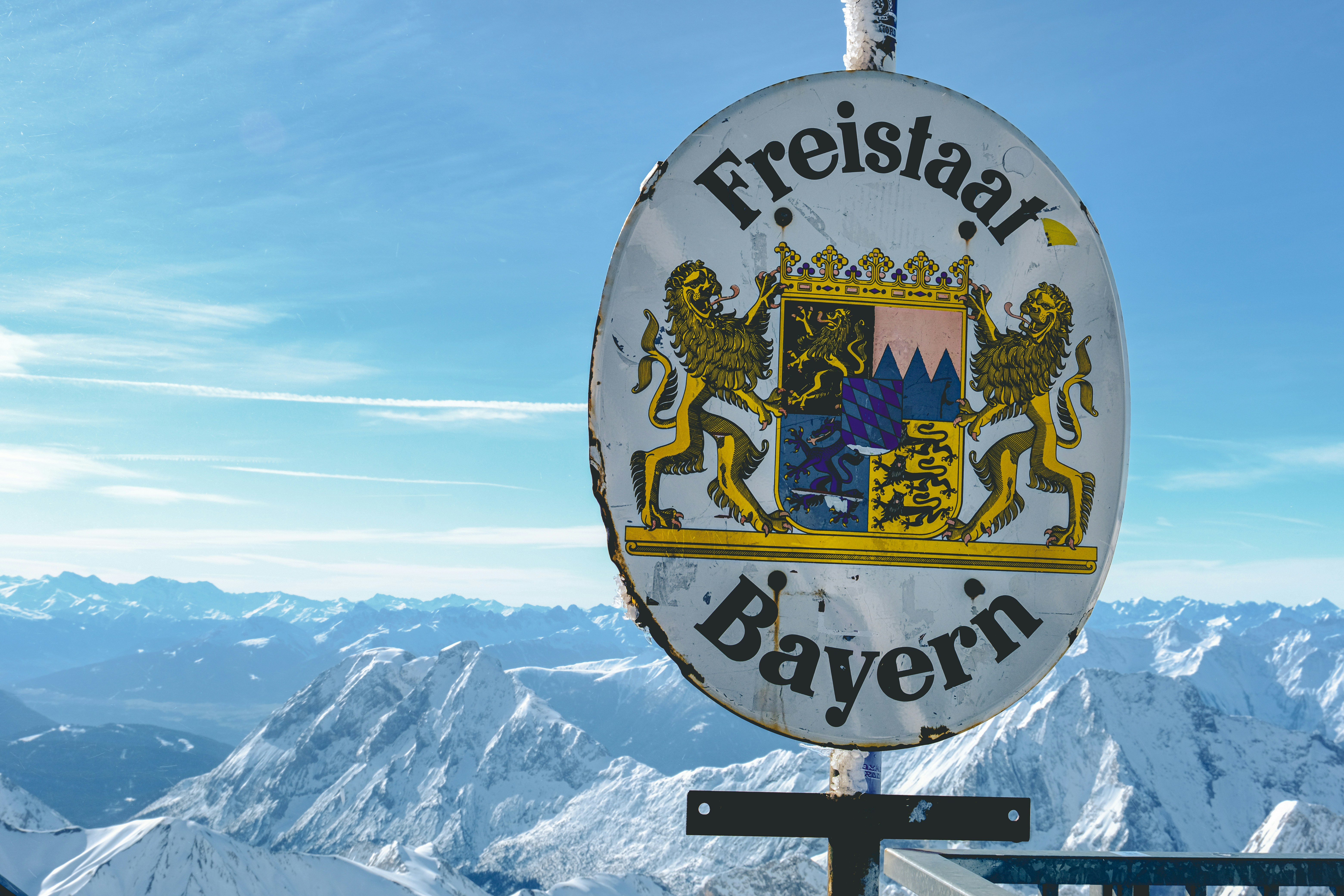 Signpost for Freistaat Bayern atop snowy Alps