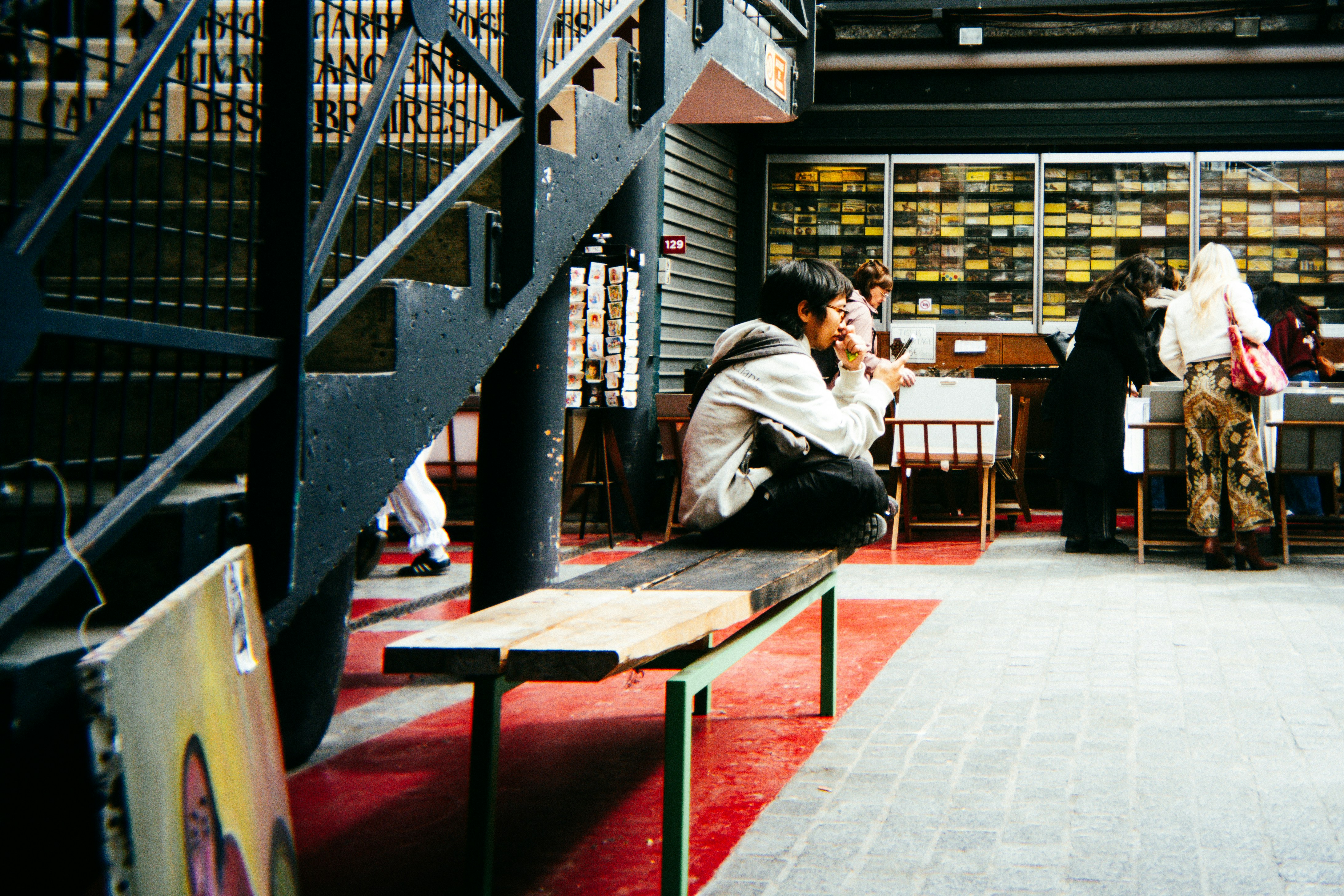 Quiet Pause by the Staged Counter: a Man in Hooded Jacket Amid a Busy Café Scene