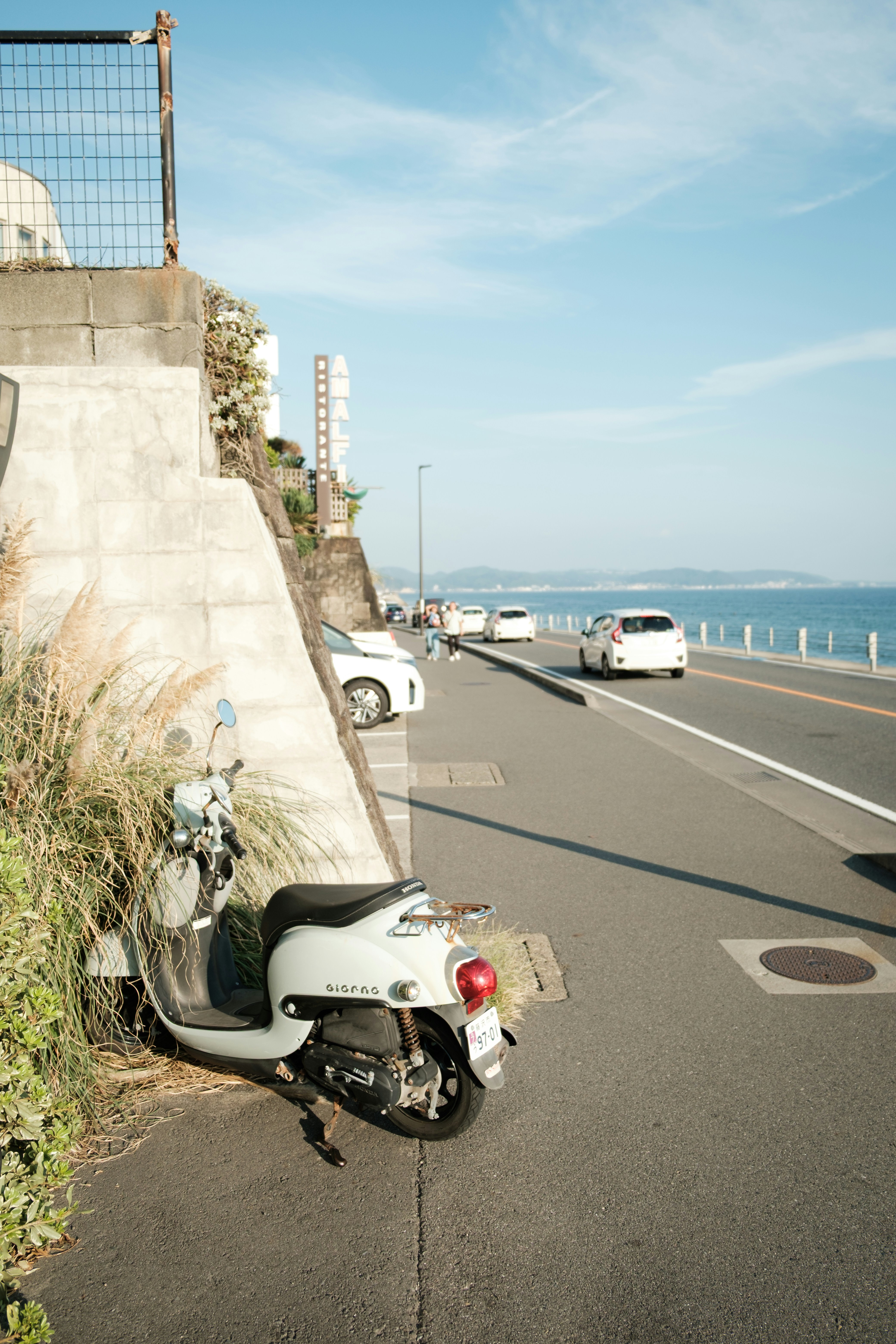 Scooter by the Sea Wall: Quiet Street, Oceanic Horizon