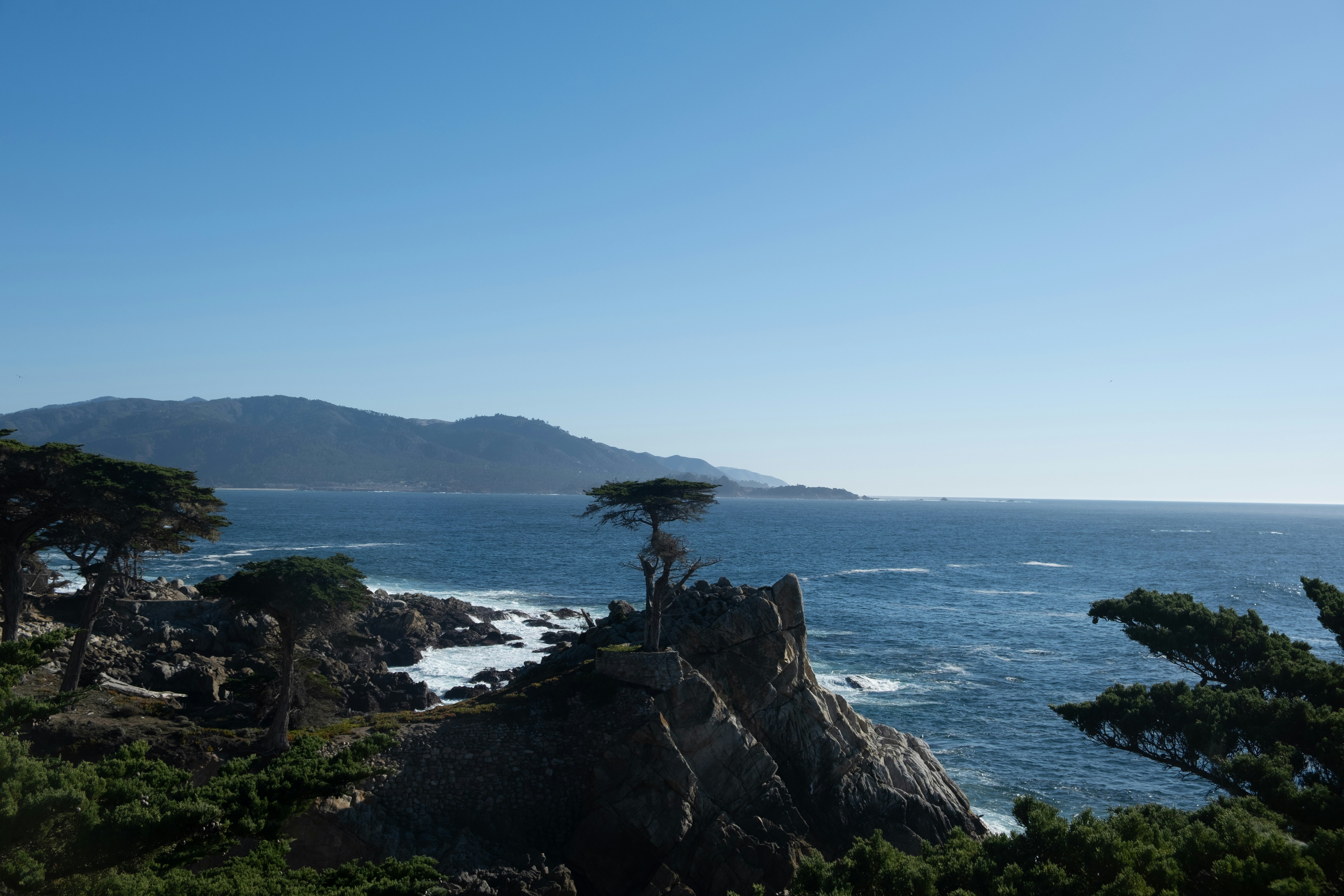 Rocky shoreline silhouette beneath a clear coastal sky
